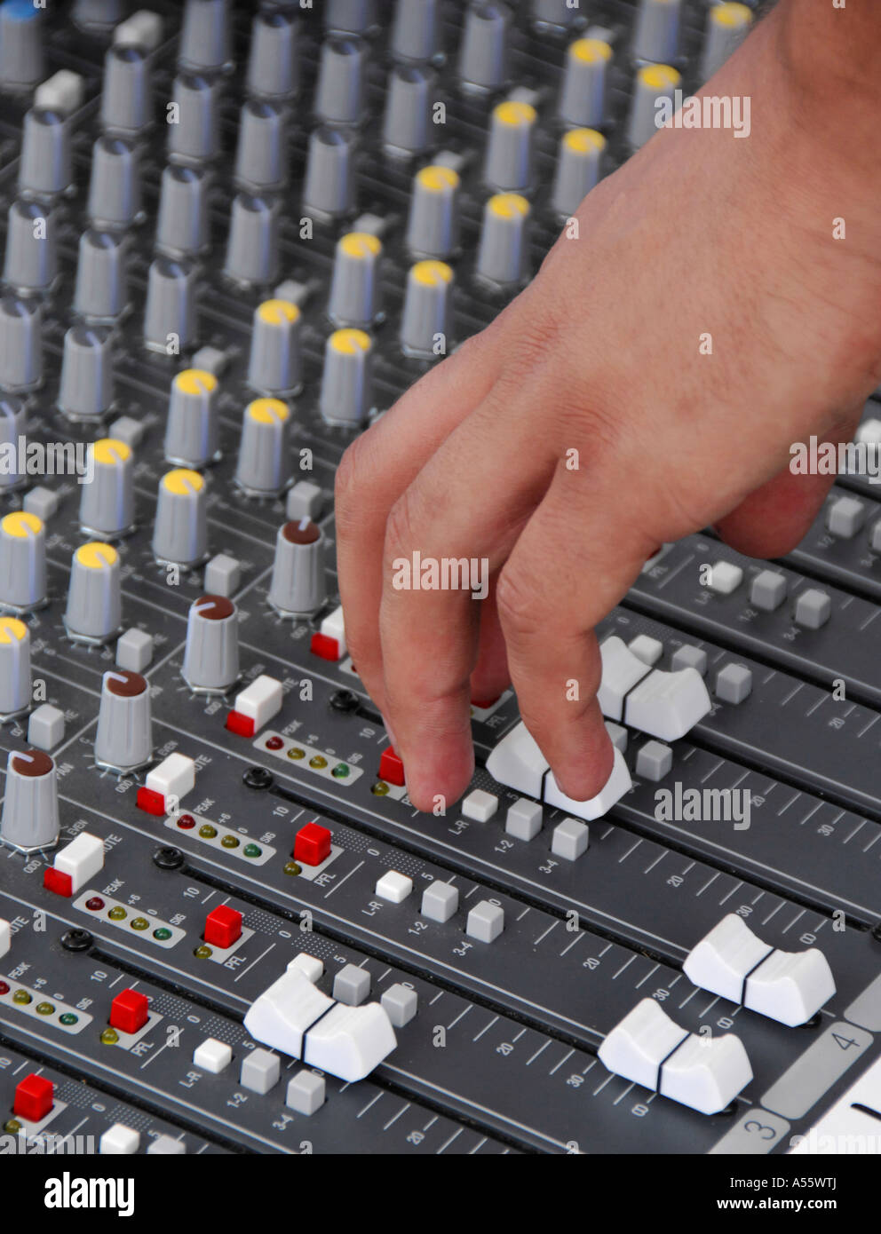 Hand on sound mixer audio console faders and equalisation controls in a ...