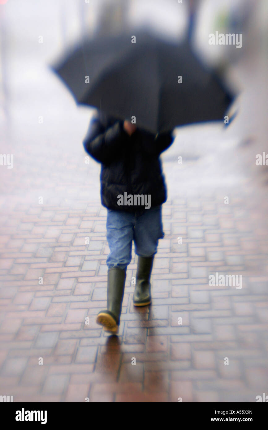 boy in wellington boots walking along pavement with umbrella Stock ...
