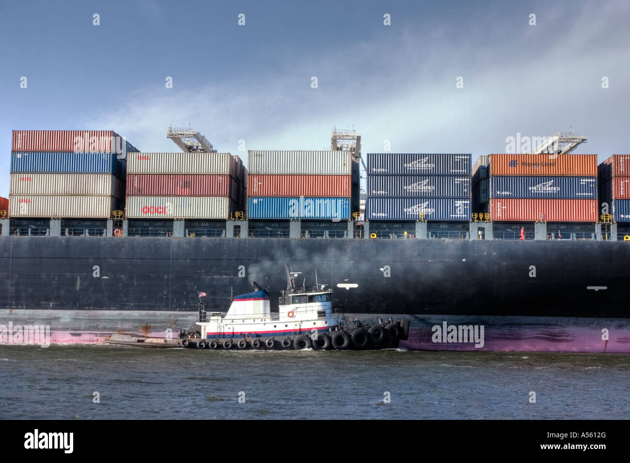 A large cargo ship loaded with shipping containers escorted by a ...