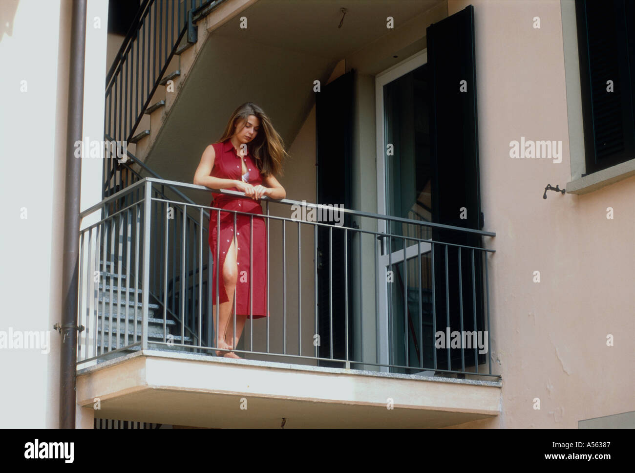 An attractive young woman with long hair in a red dress on hotel ...