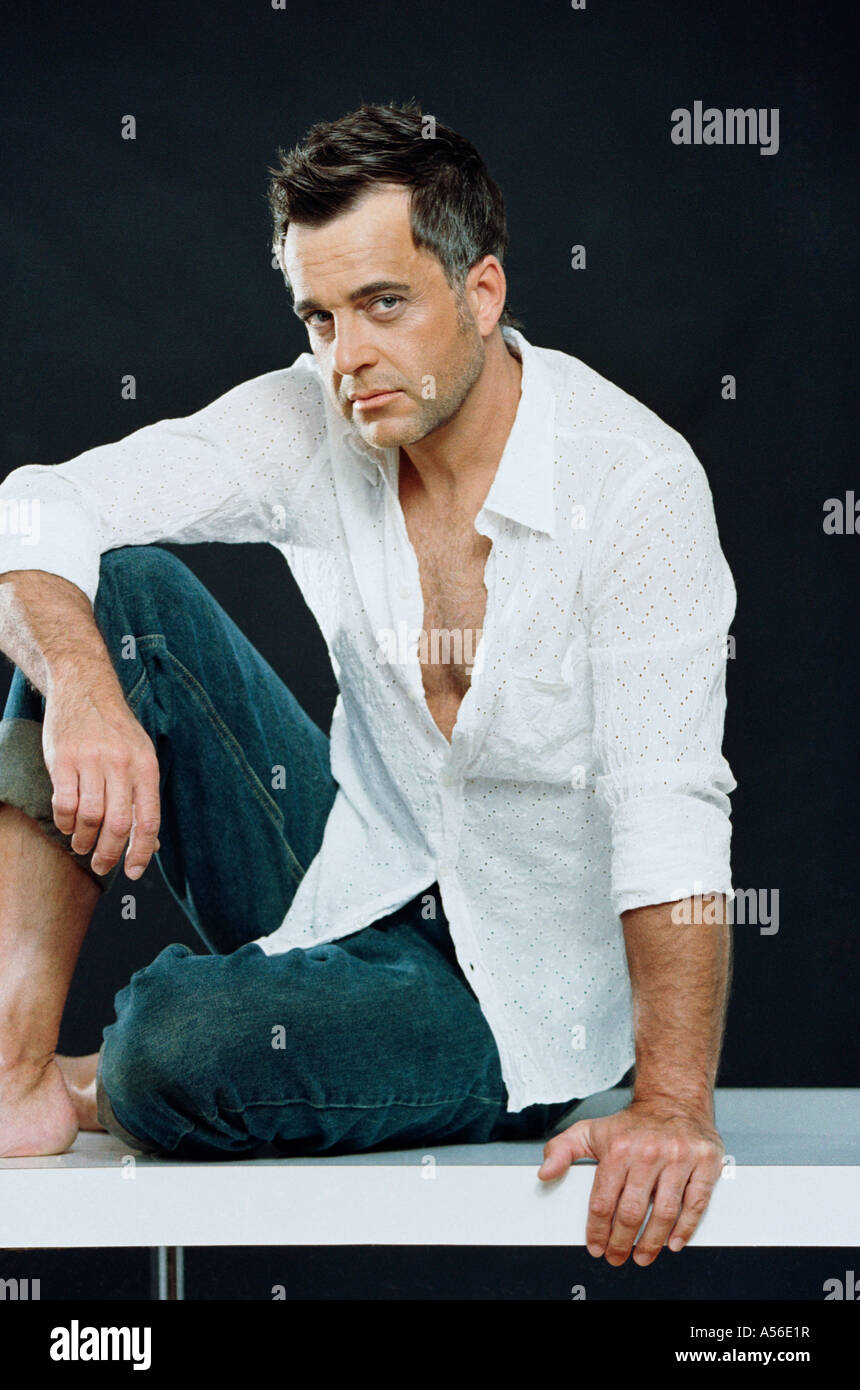 Man sitting on shelf, portrait Stock Photo - Alamy