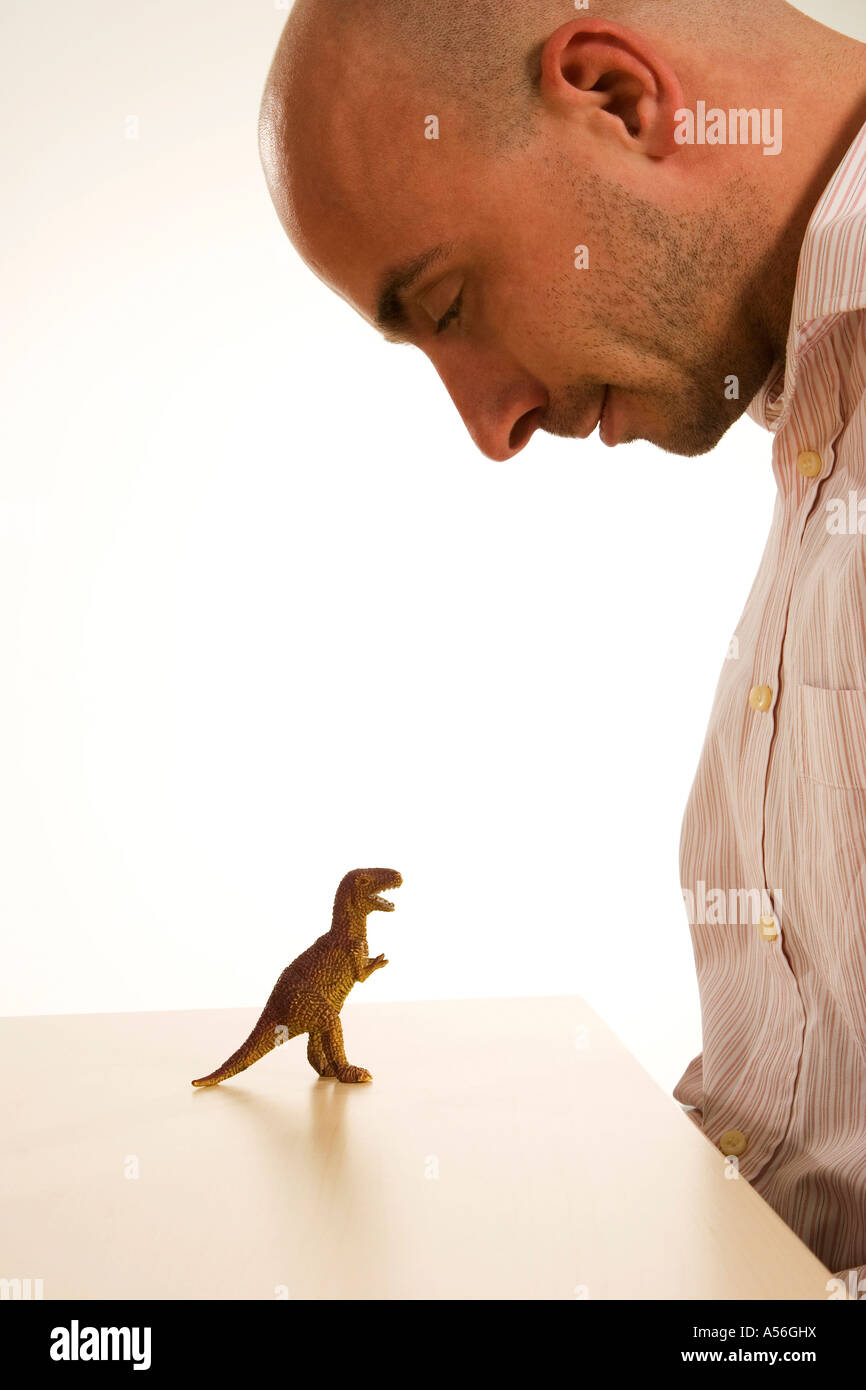 Man looking at toy dinosaur on table Stock Photo - Alamy