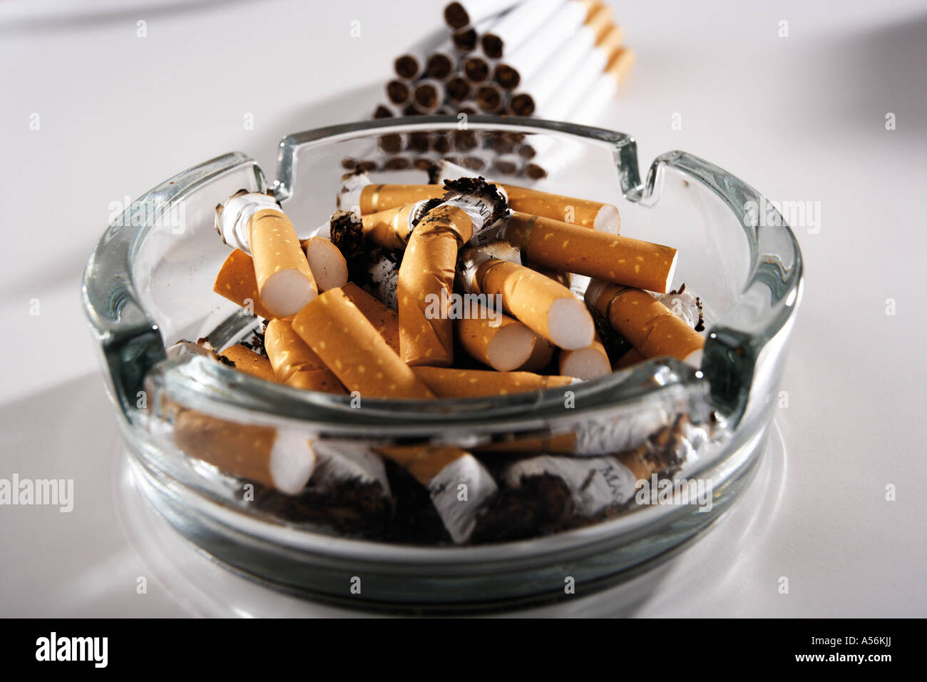 Full ashtray in front of cigarettes pile Stock Photo - Alamy