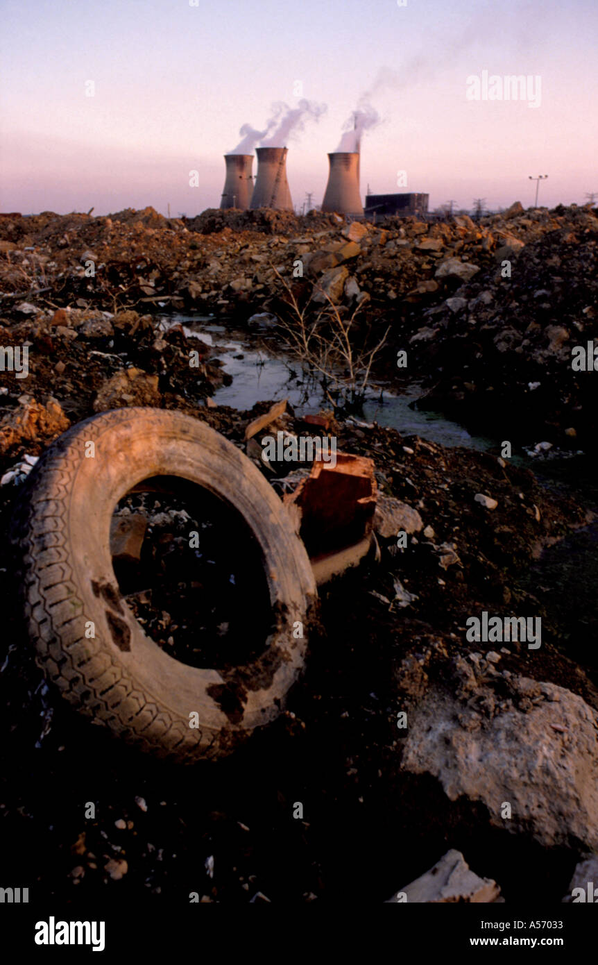 Rubbish dumped on waste ground with cooling towers of a power station ...
