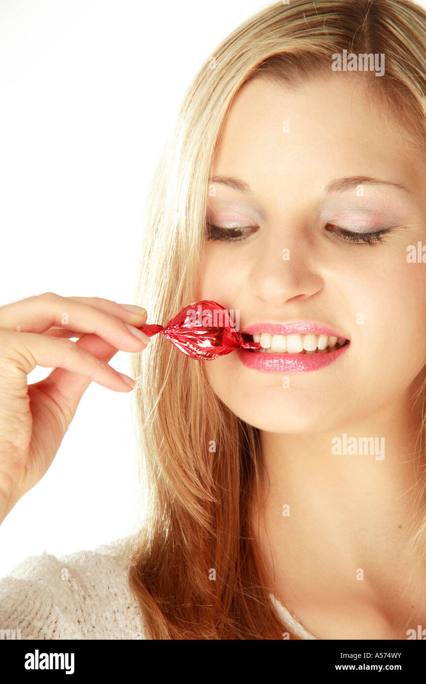 Young woman holding wrapped candy between teeth, close-up Stock Photo ...