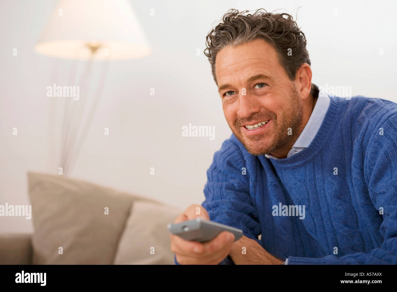 Man sitting on sofa, holding remote control Stock Photo - Alamy