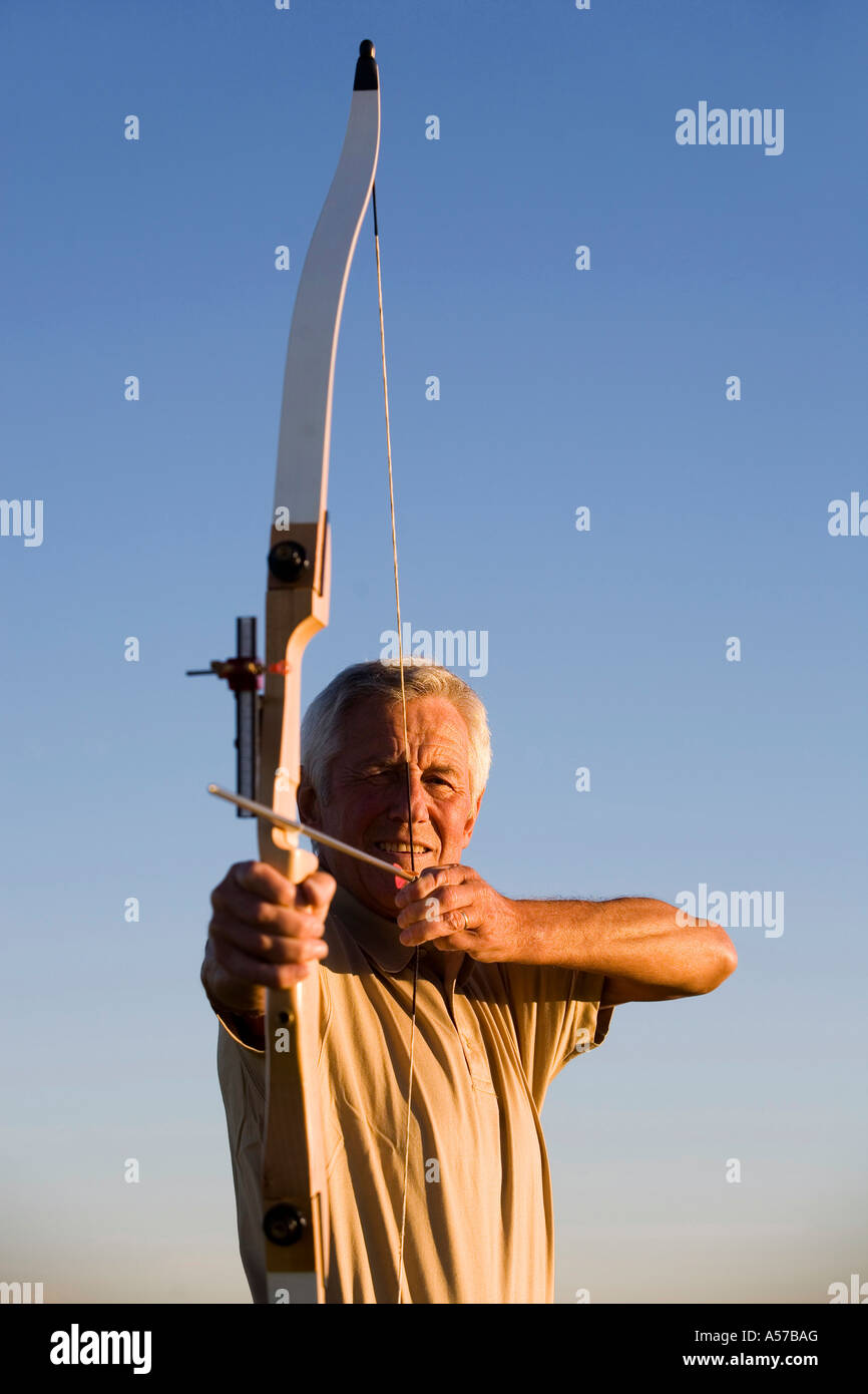 Senior adult man using bow and arrow Stock Photo - Alamy