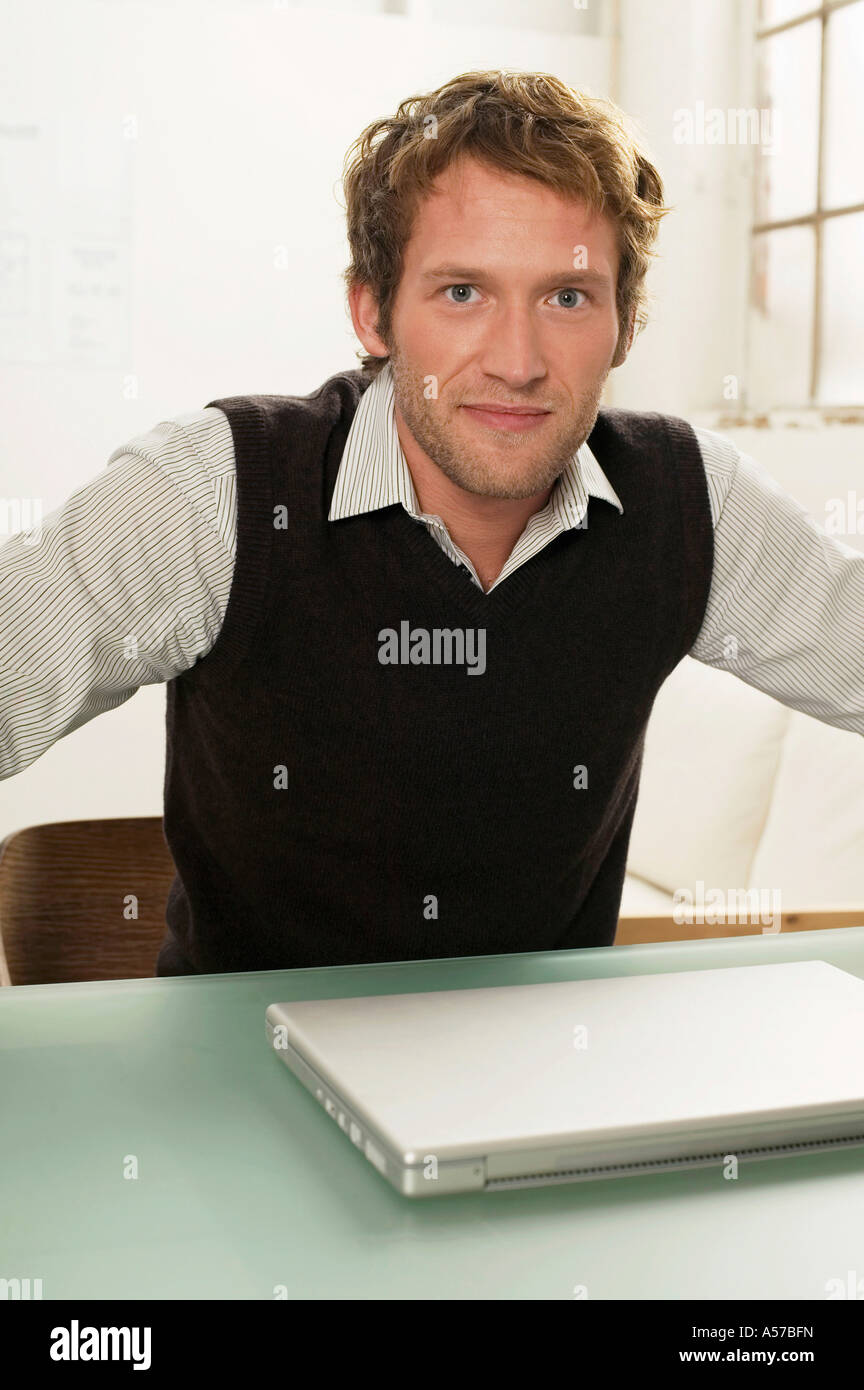 Young man sitting on desk Stock Photo - Alamy