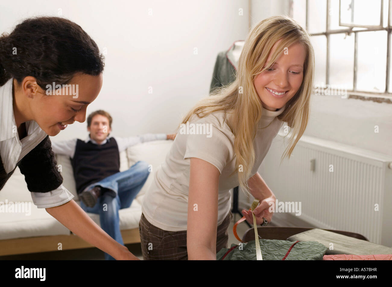 Two young women measuring cloth Stock Photo - Alamy