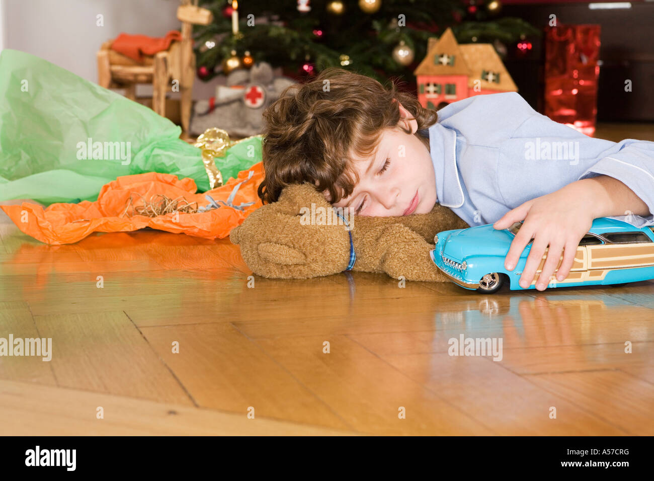 Boy sleeping under Christmas tree, holding toy car Stock Photo - Alamy