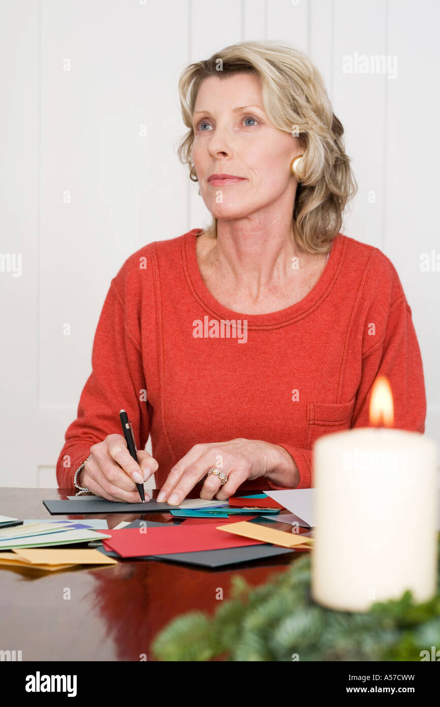 Woman writing Christmas cards, looking away, portrait Stock Photo - Alamy