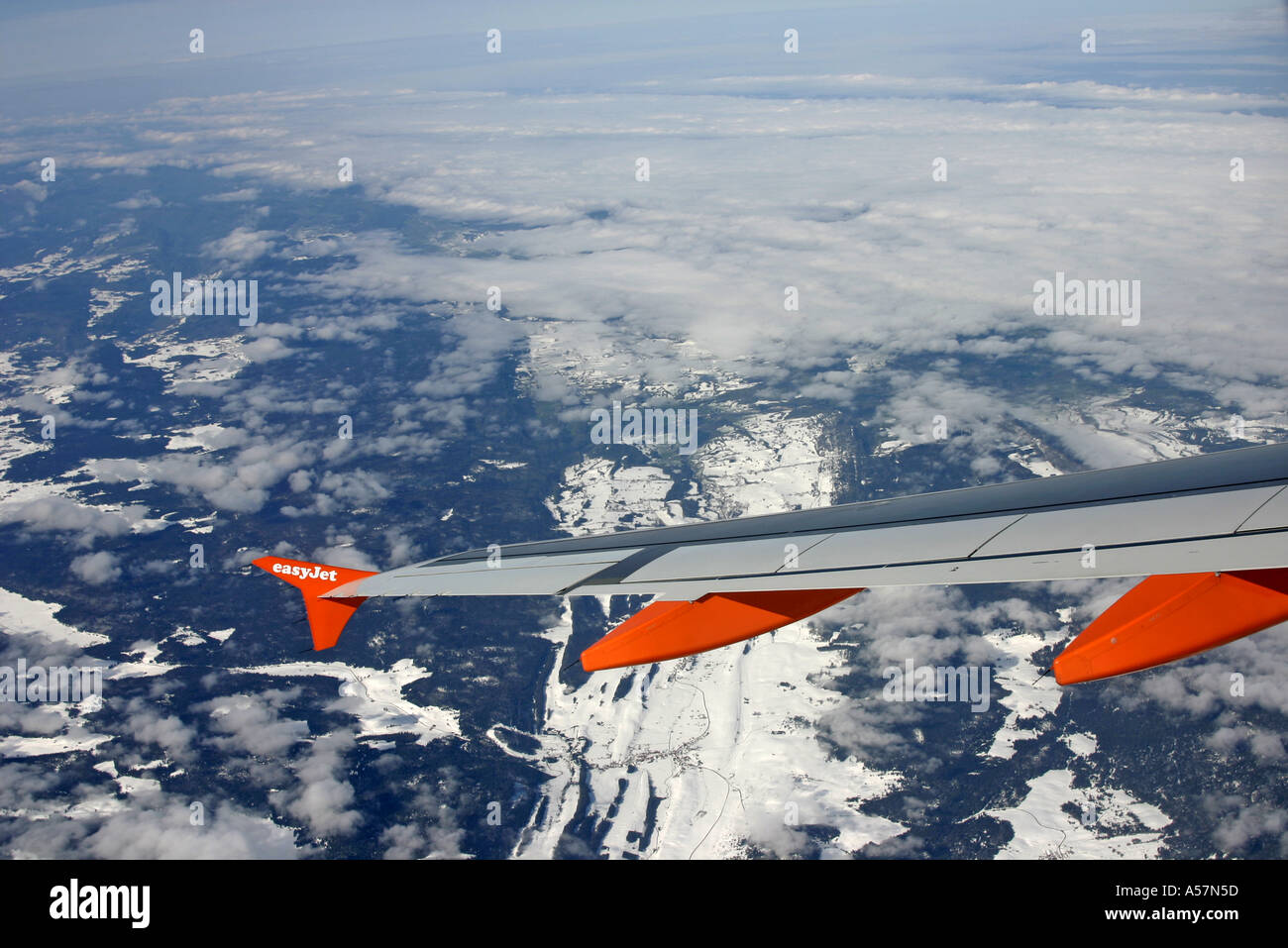 Aerial view of Easyjet aircraft wing and wingtip above snowy mountains ...