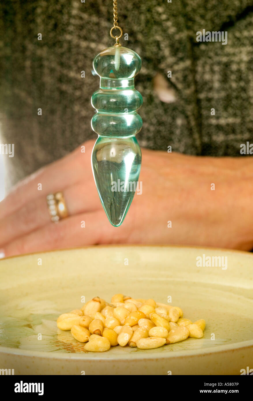 woman using a pendulum to allergy test food Stock Photo - Alamy