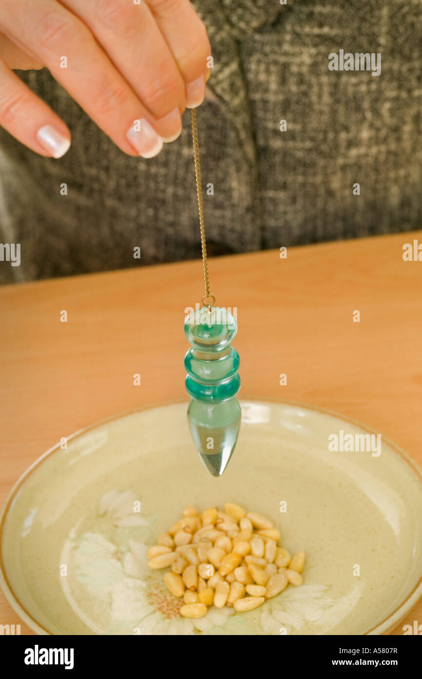 woman using a pendulum to allergy test food Stock Photo - Alamy