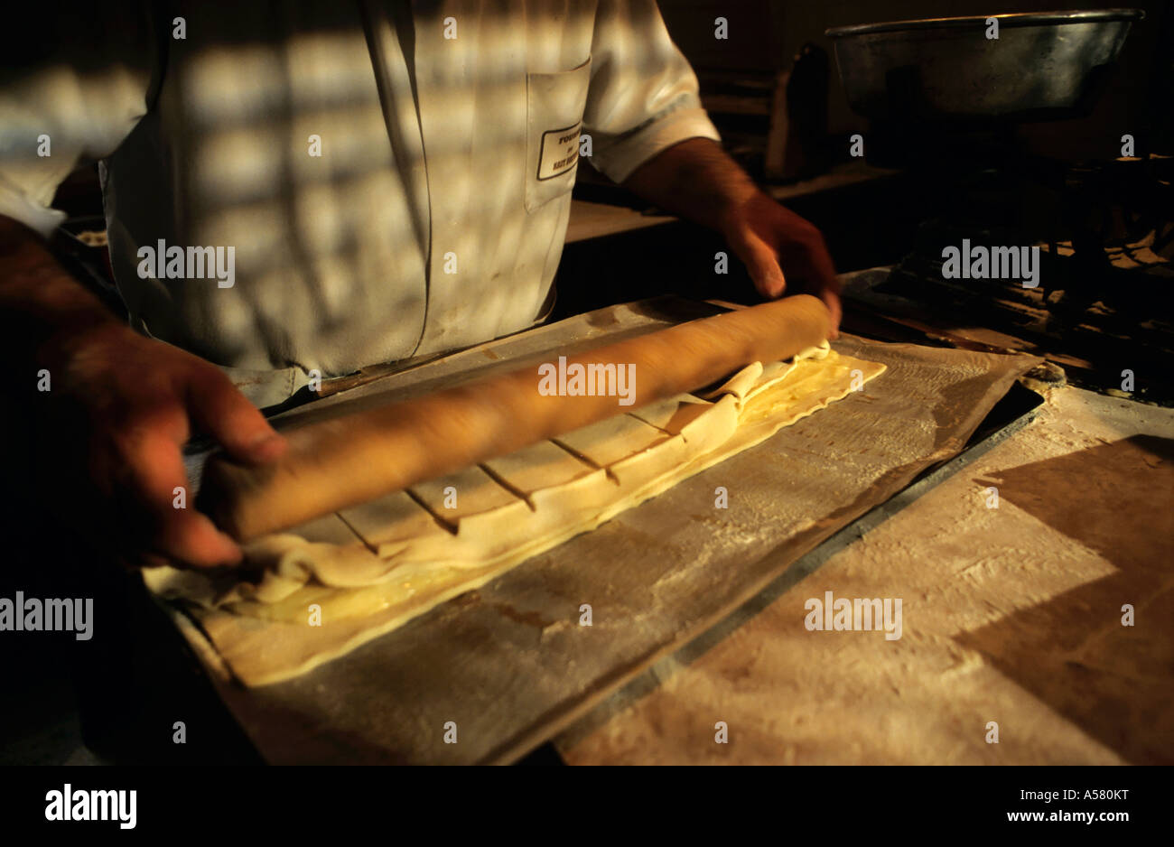 Baker rolling pastry with a rolling pin inside a bakery, France Stock ...
