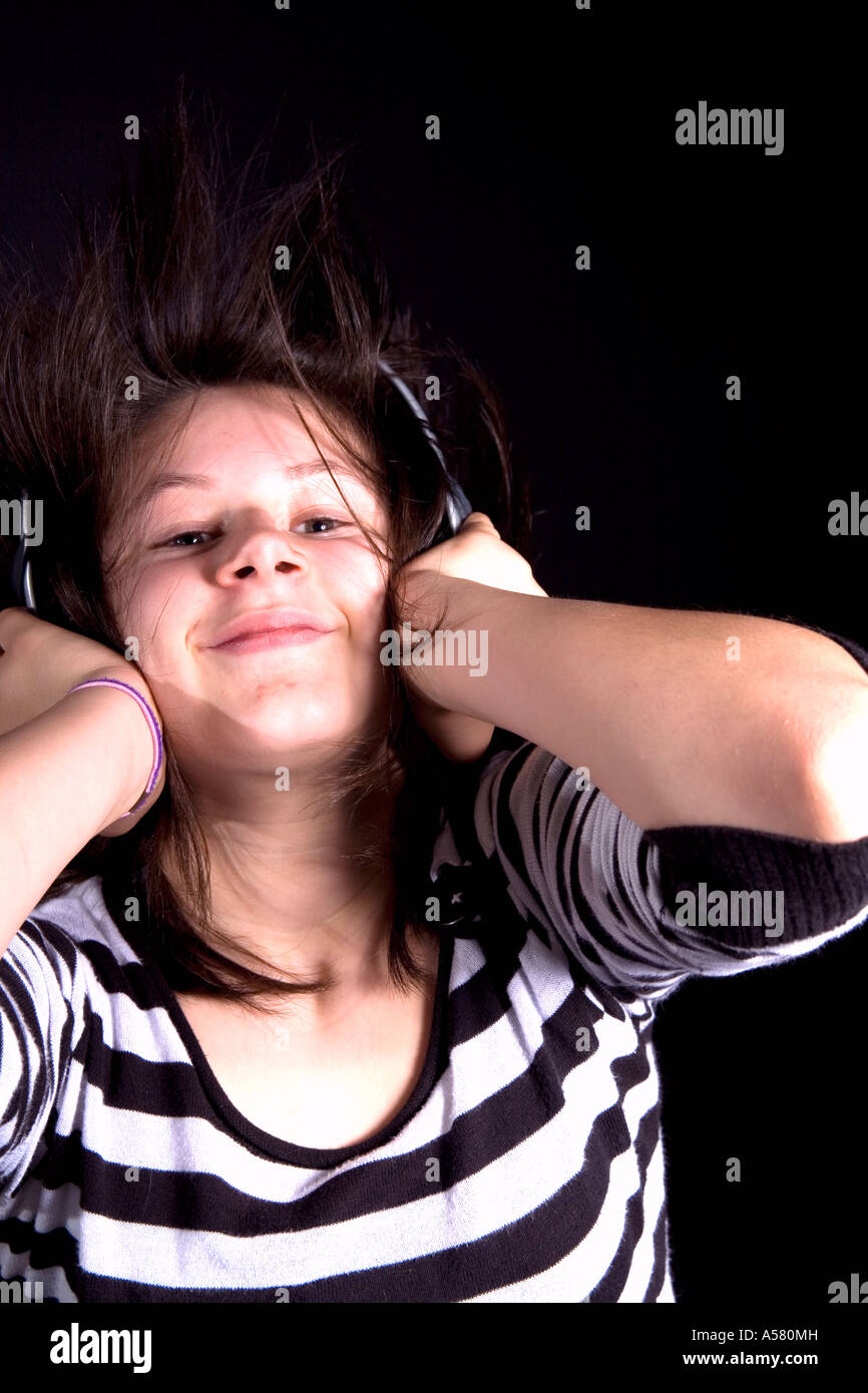Action shot of young girl swinging her head and hair whilst listenging ...