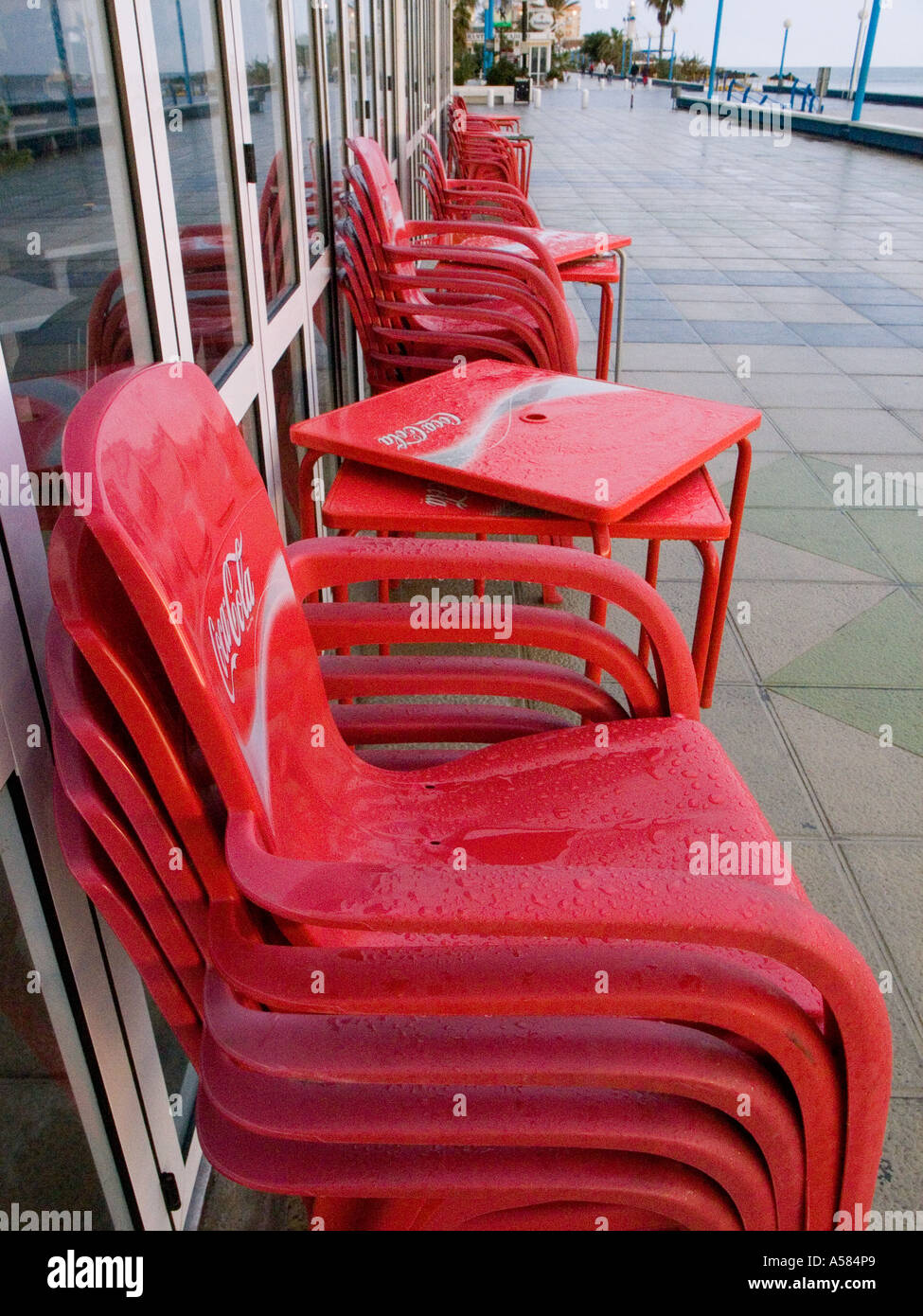 Red cafe chairs stacked up during the winter rain on the beach ...