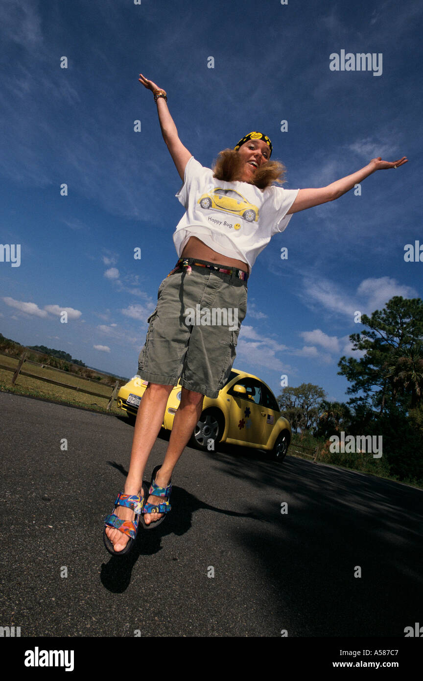 Young hippie woman jumping with her arms stretched out with a yellow ...