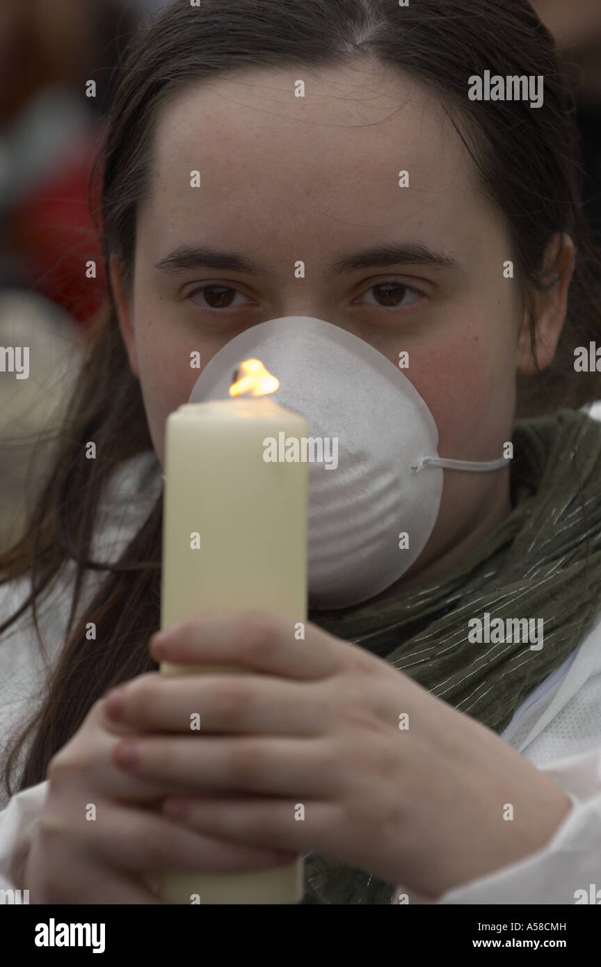 Young woman wearing a mask holding a lit pillar candle at anti-nuclear ...