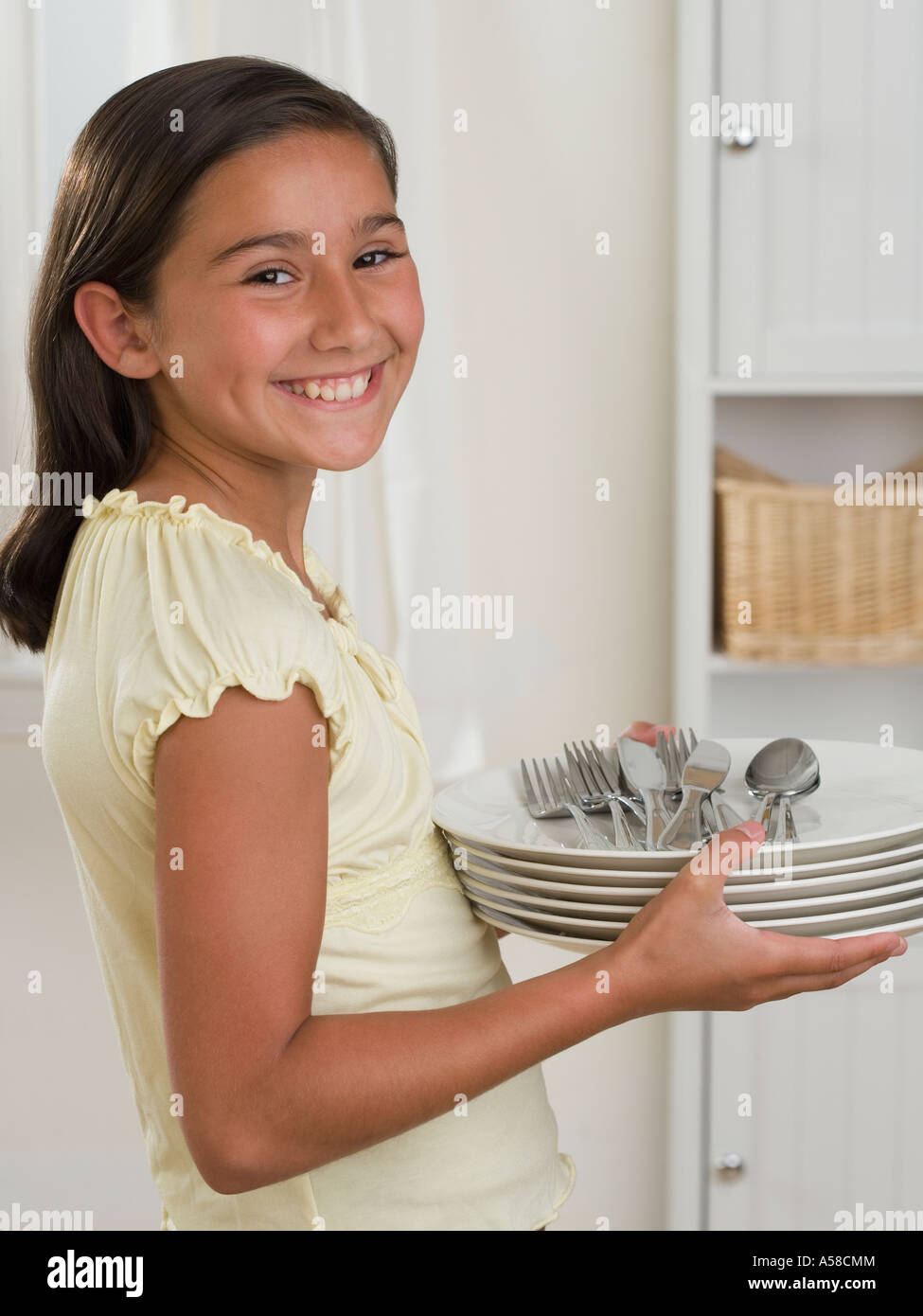 Hispanic girl smiling with stack of plates and silverware Stock Photo ...