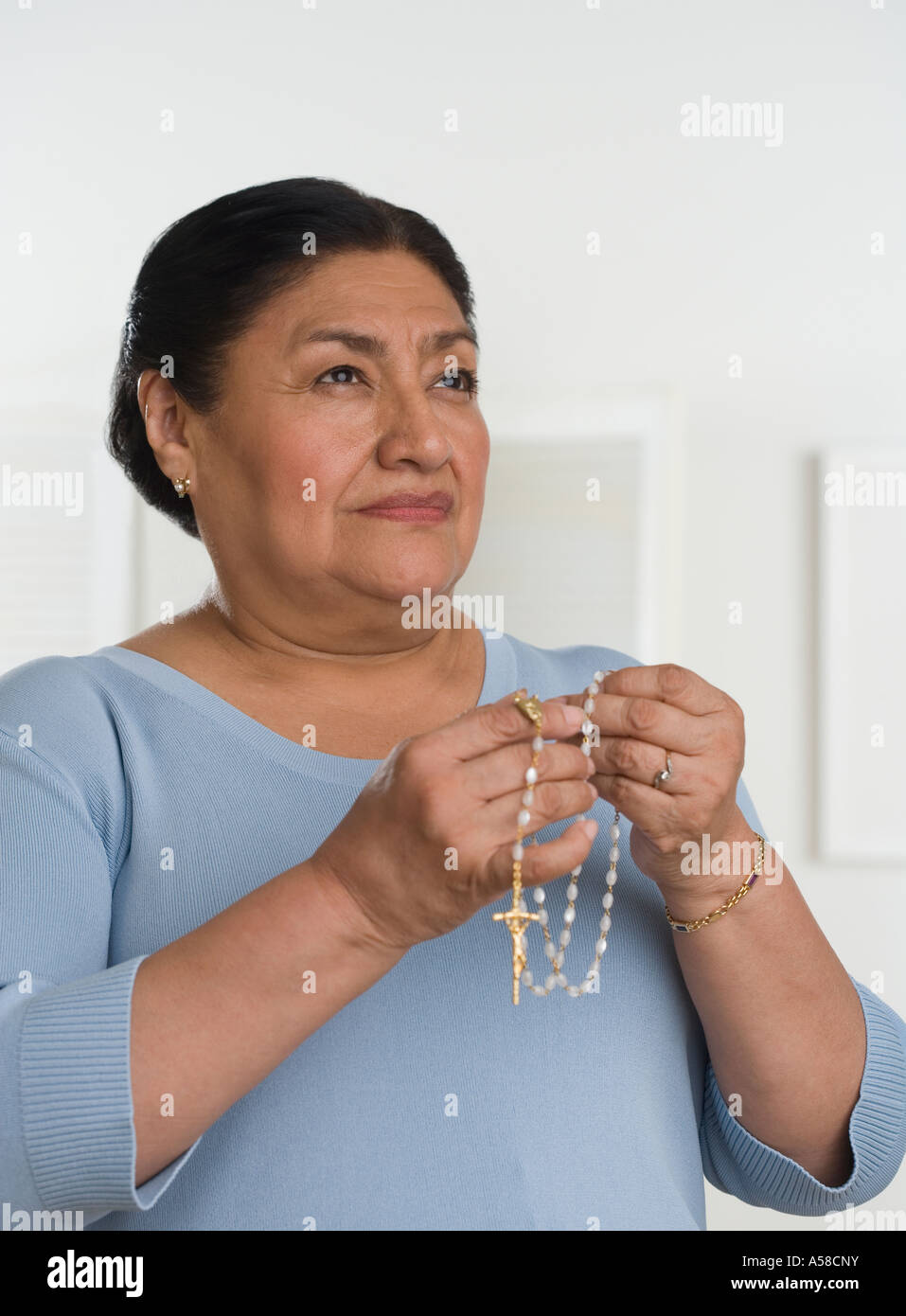 Senior Hispanic woman praying with rosary Stock Photo - Alamy