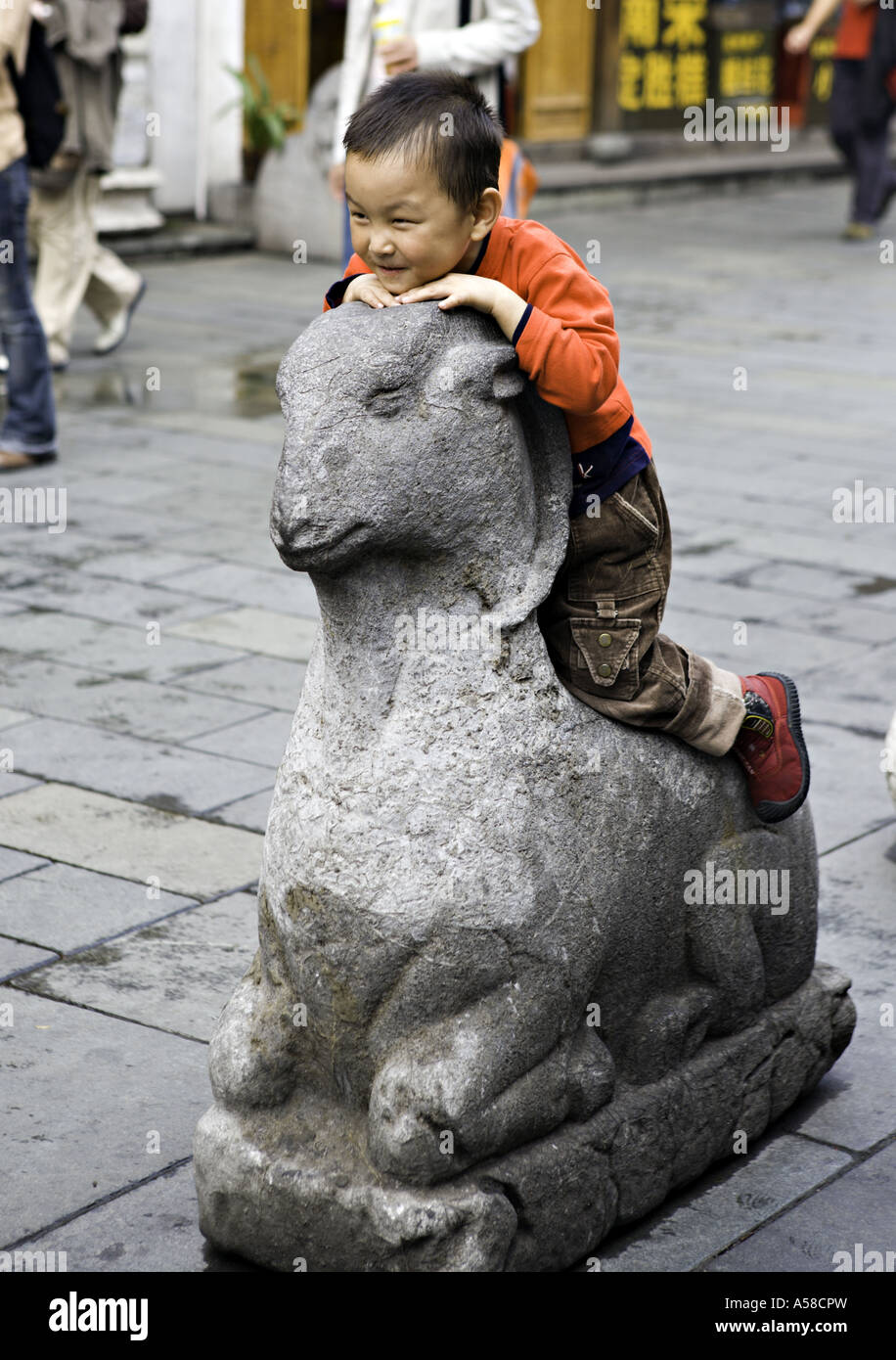 CHINA SHANGHAI Young Chinese boy poses on a statue on the sidewalk in ...