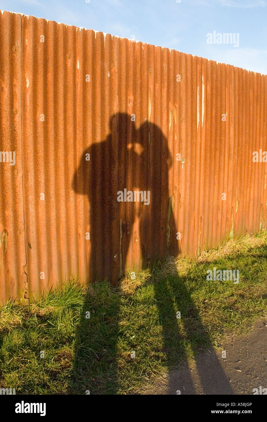 A kissing couple silhouetted on a rusty corrugated iron fence Stock ...