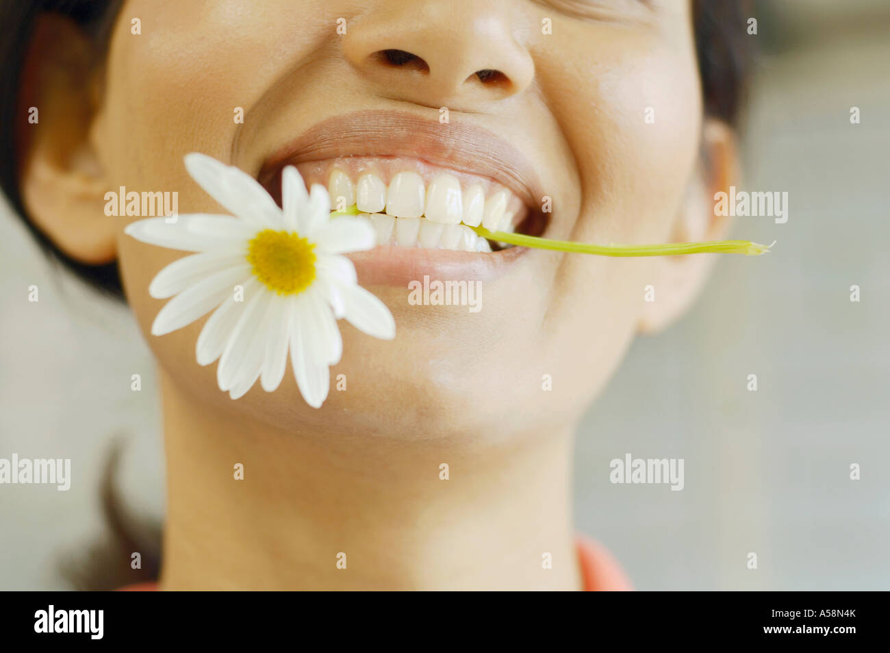 Woman smiling with flower in her teeth Stock Photo - Alamy