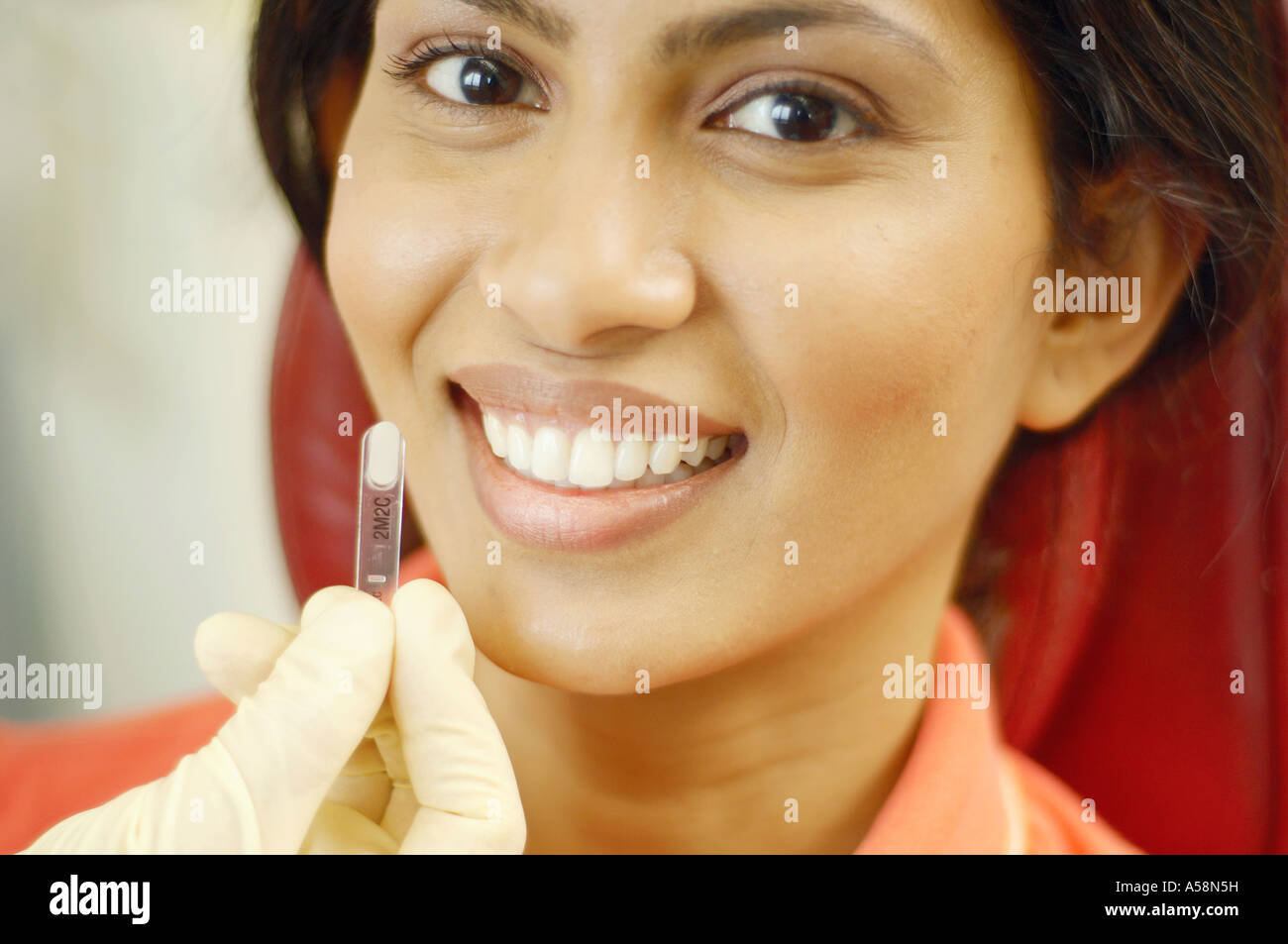 Tooth color sample being held up next to Indian woman s teeth Stock ...