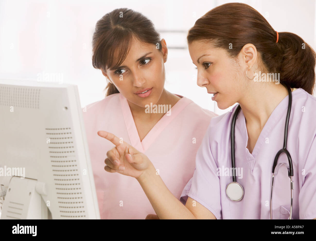 Two nurses talking in front of computer Stock Photo - Alamy