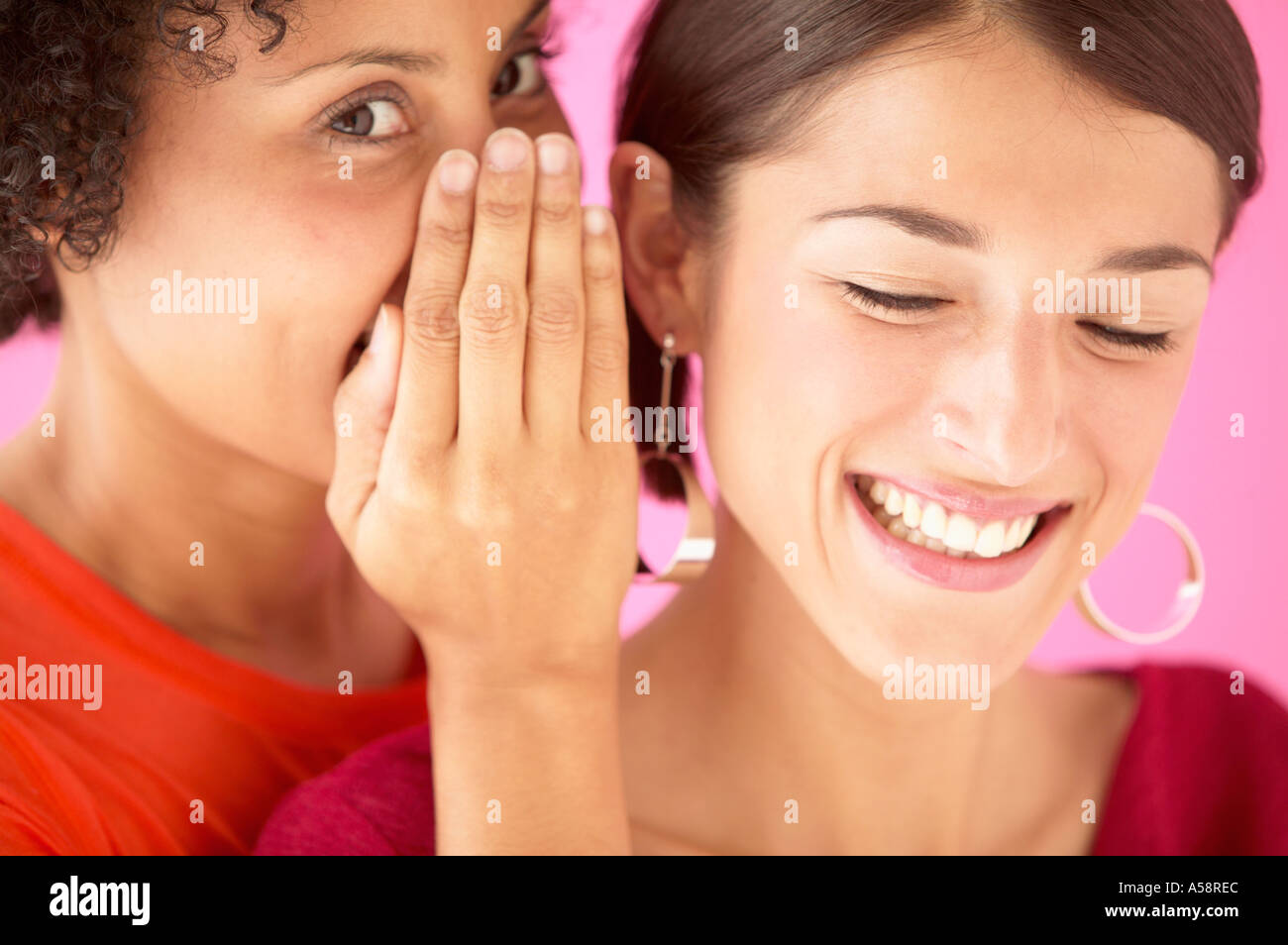 Woman whispering in friend s ear Stock Photo - Alamy