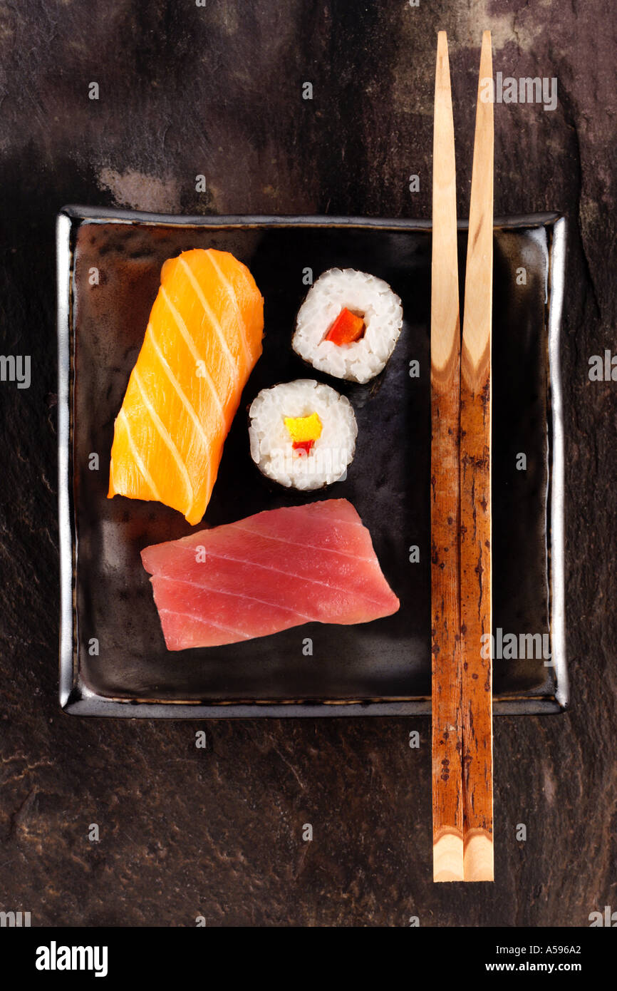 BLACK SQUARE PLATE WITH TWO PIECES OF RAW FISH AND TWO CIRCLES OF ...