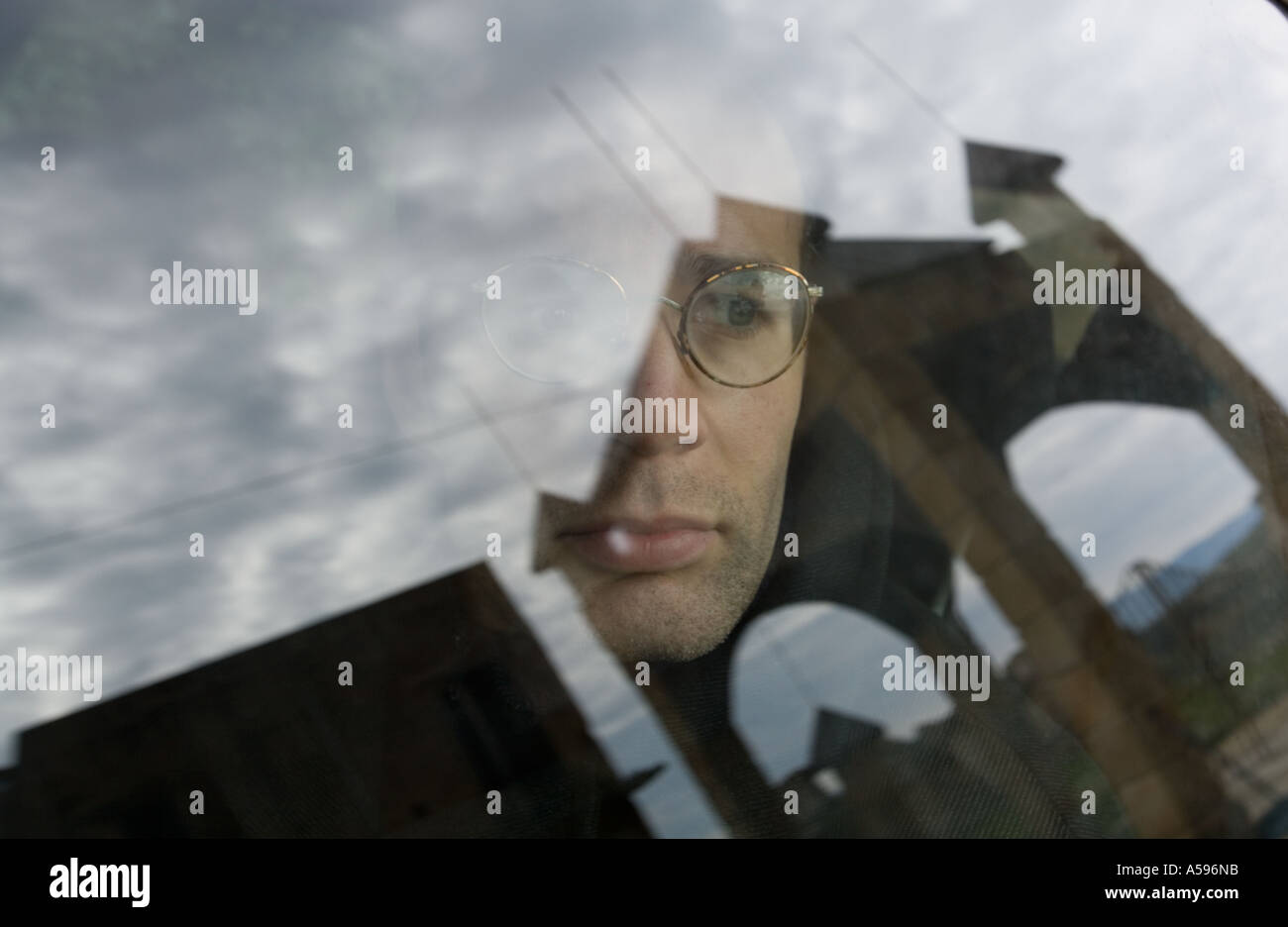 Portrait of a man looking outside the window with a nostalgic gaze ...
