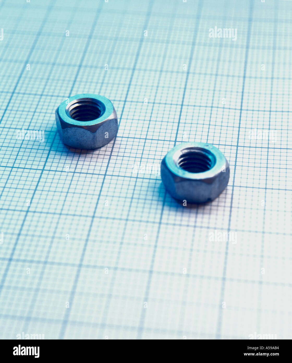 Engineering study; two galvanised steel nuts on blue graph paper Stock ...