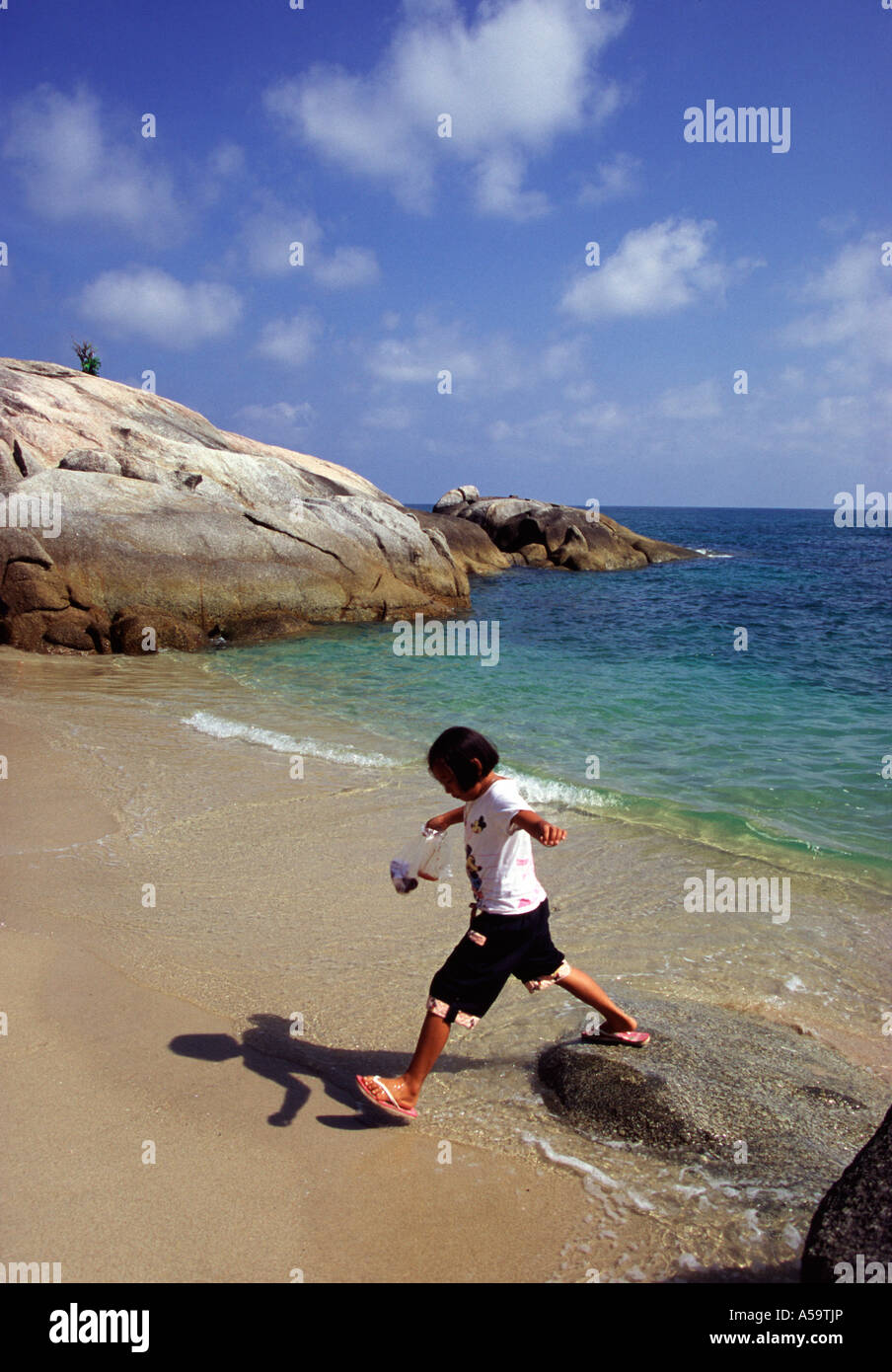 Young girl jumping across the incoming wave Stock Photo - Alamy