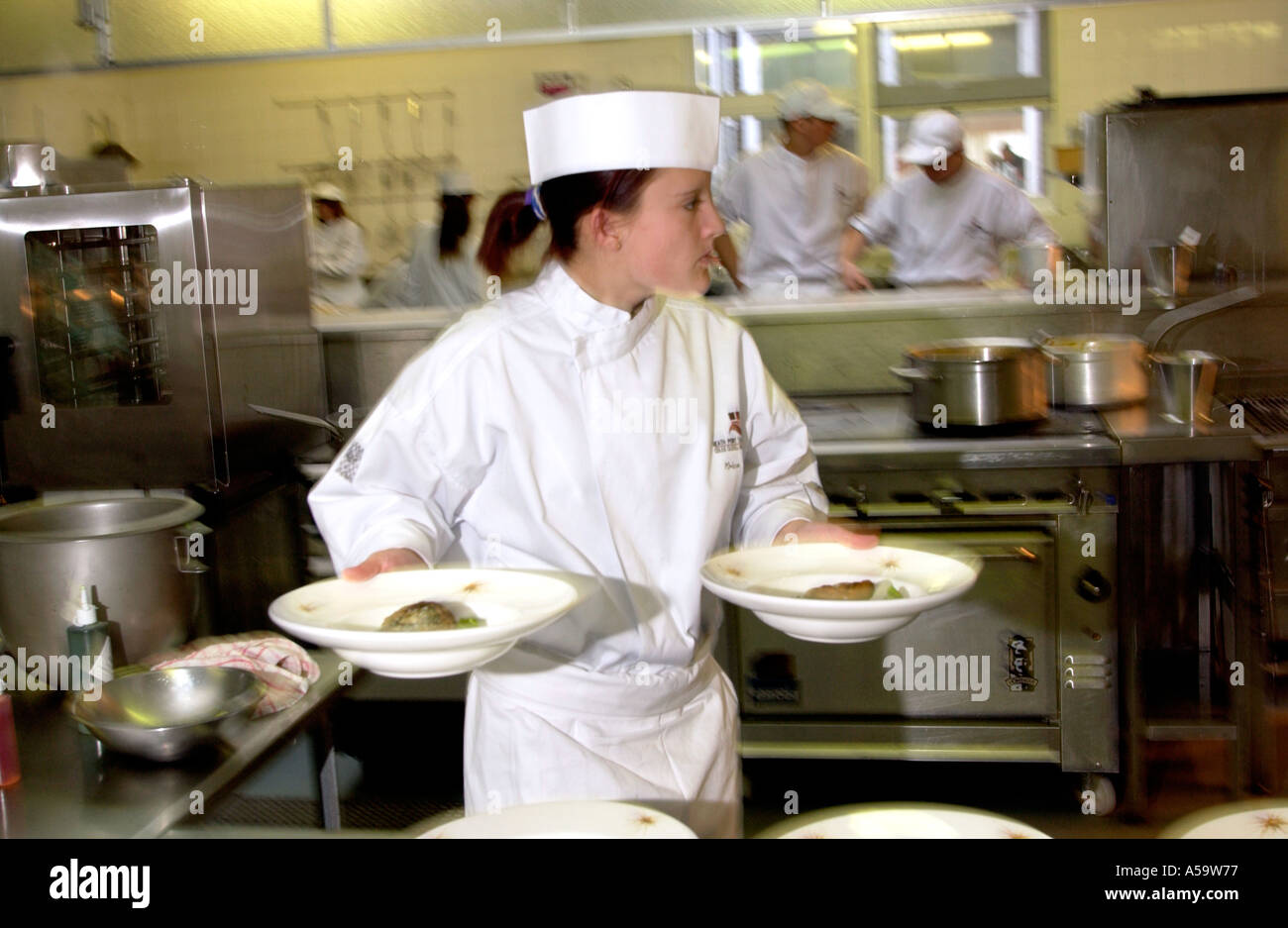 Student chef preparing food in kitchen for customers in college ...