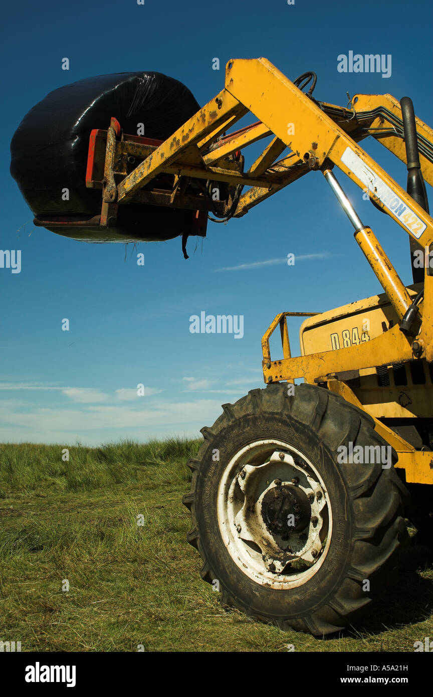 Tractor loader with big bale on Stock Photo - Alamy