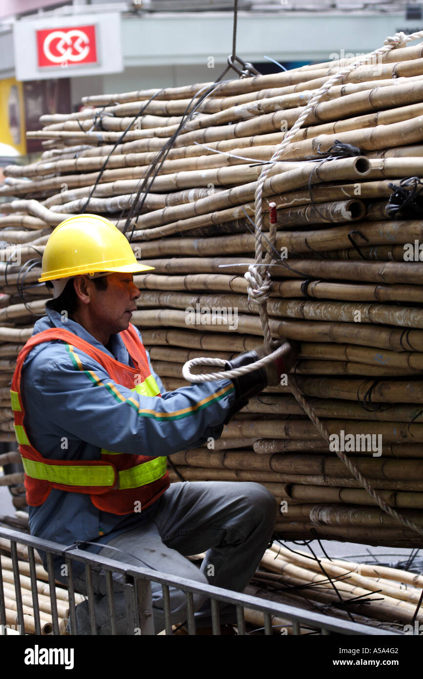 Workman guides mechanical arm in the lifting of bamboo used for ...