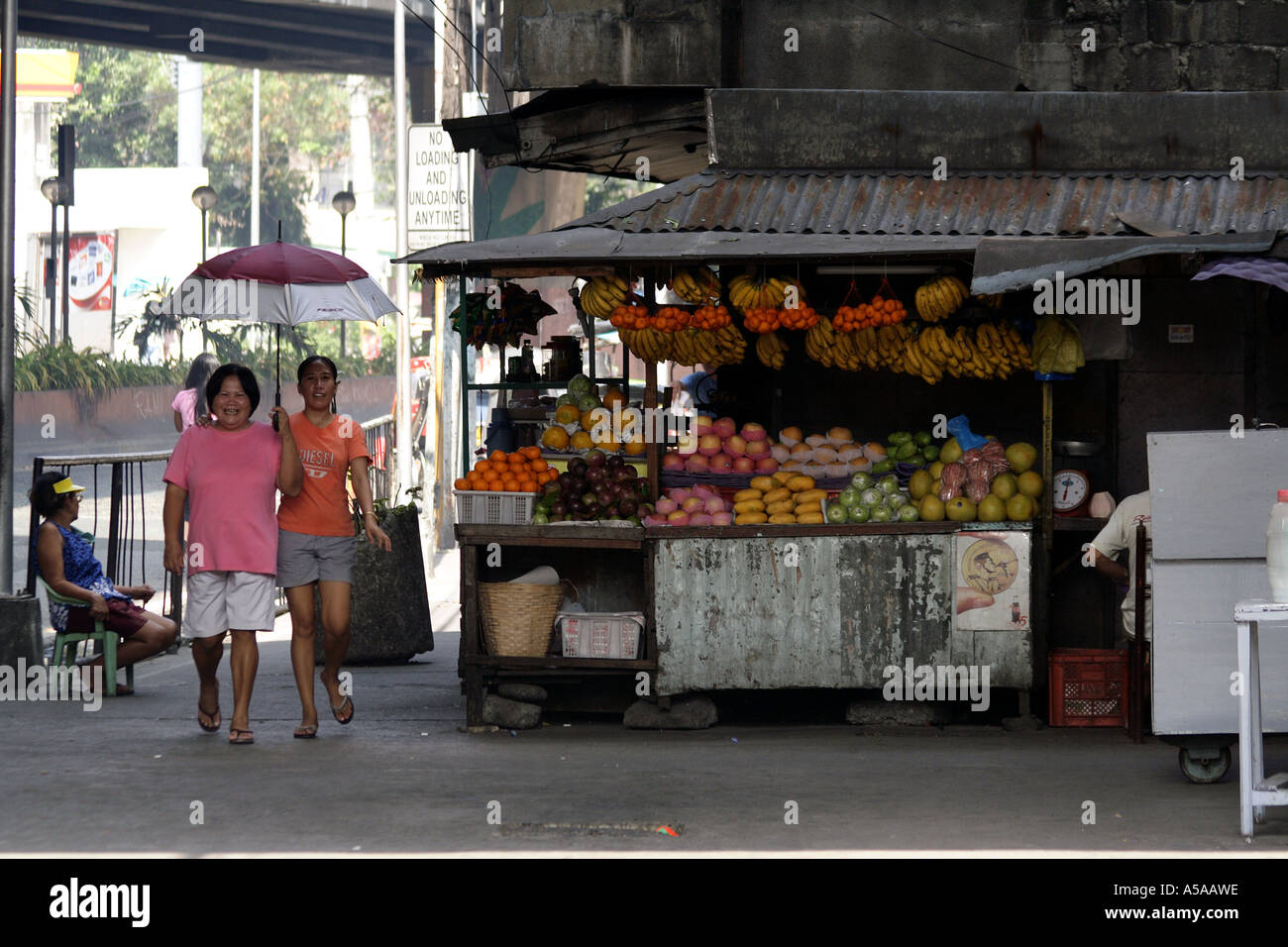 Women with a parasol and a fresh fruit stall in Manila, Philippine ...