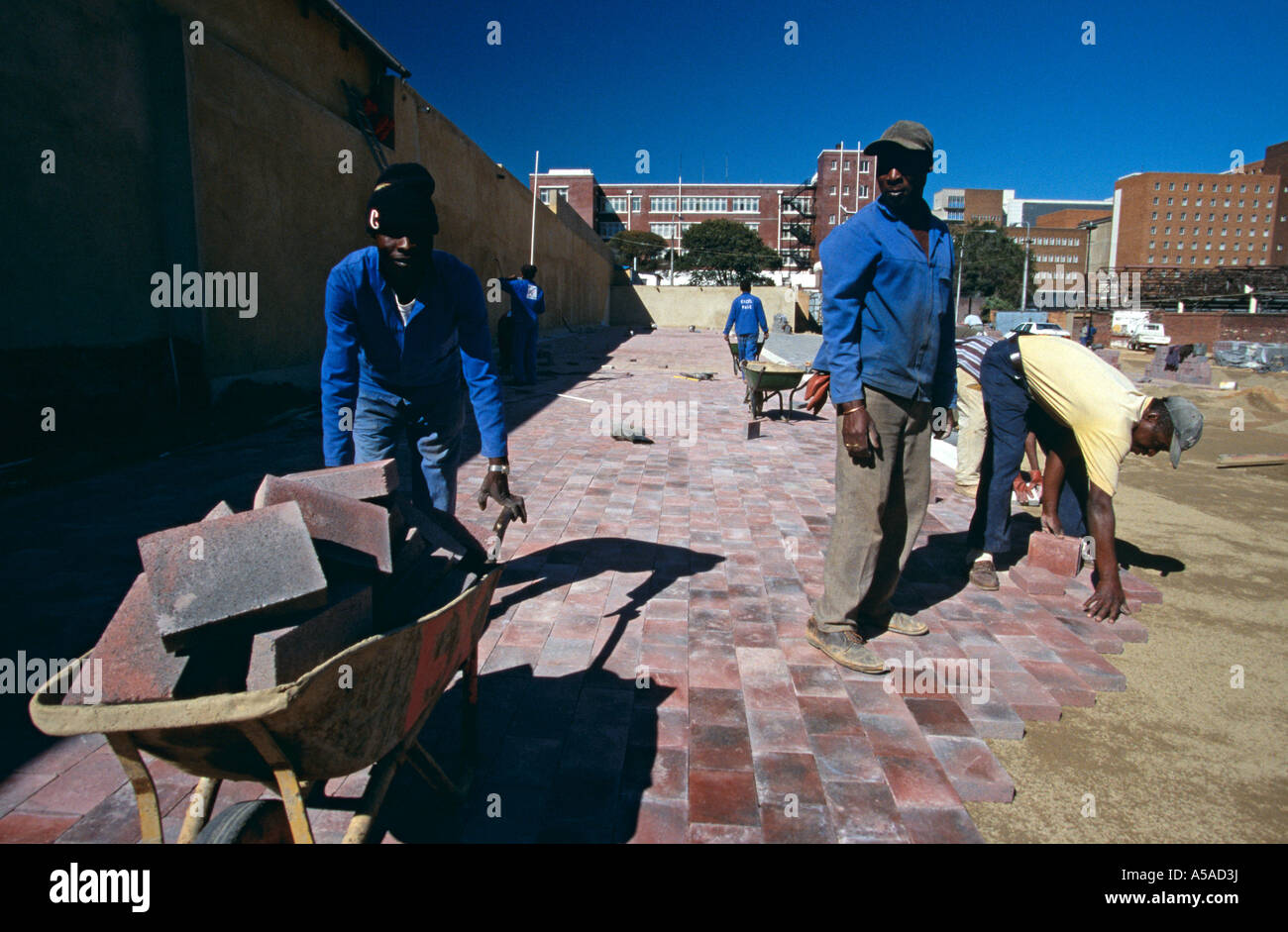 Workers laying down bricks for the floor of a building in Johannesburg ...