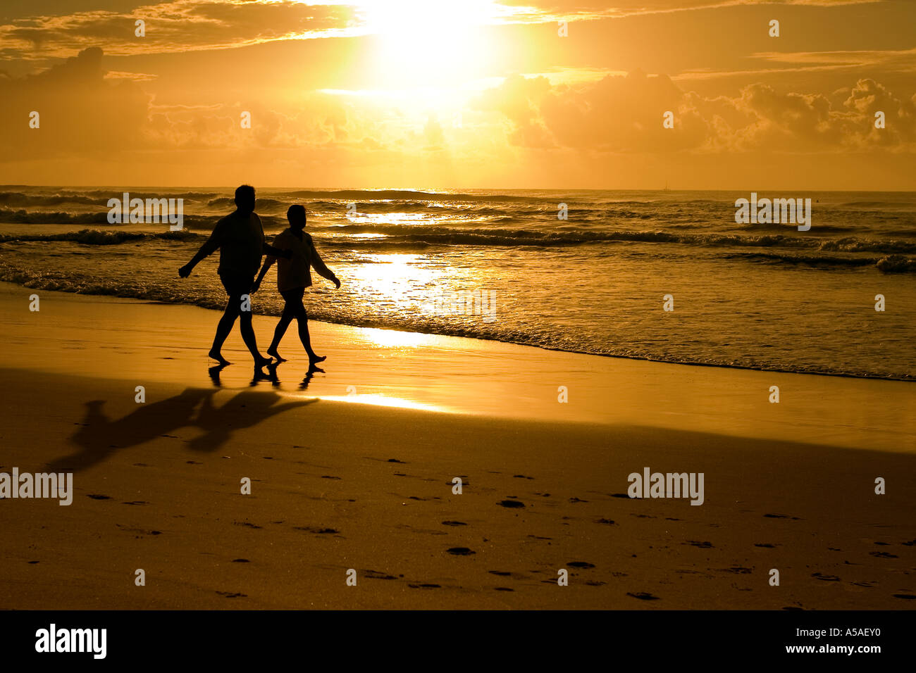 Silhouette of couple strolling along the beach Stock Photo - Alamy