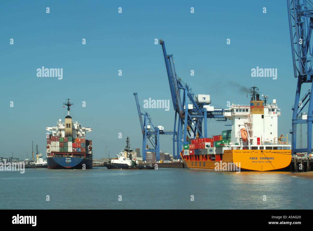Arriving cargo container ship assisted by tugboats small yellow ...