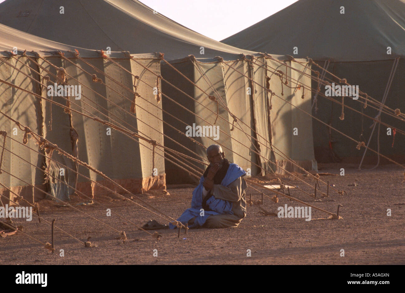 A Sahrawi man sitting outside tents at a refugee camp in Tindouf ...