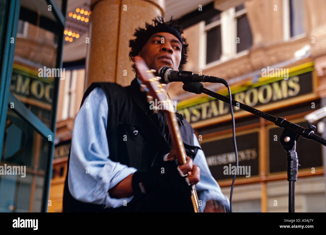 A street performer singing with his guitar on a street in London Stock ...
