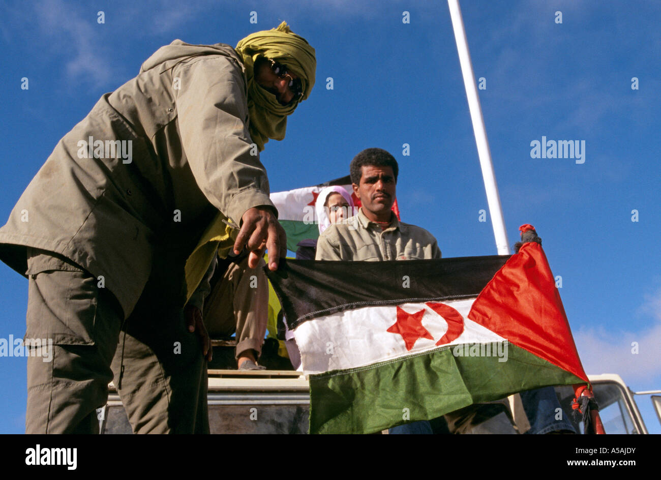 A sahrawi man standing on his jeep with the Western Sahara flag during ...