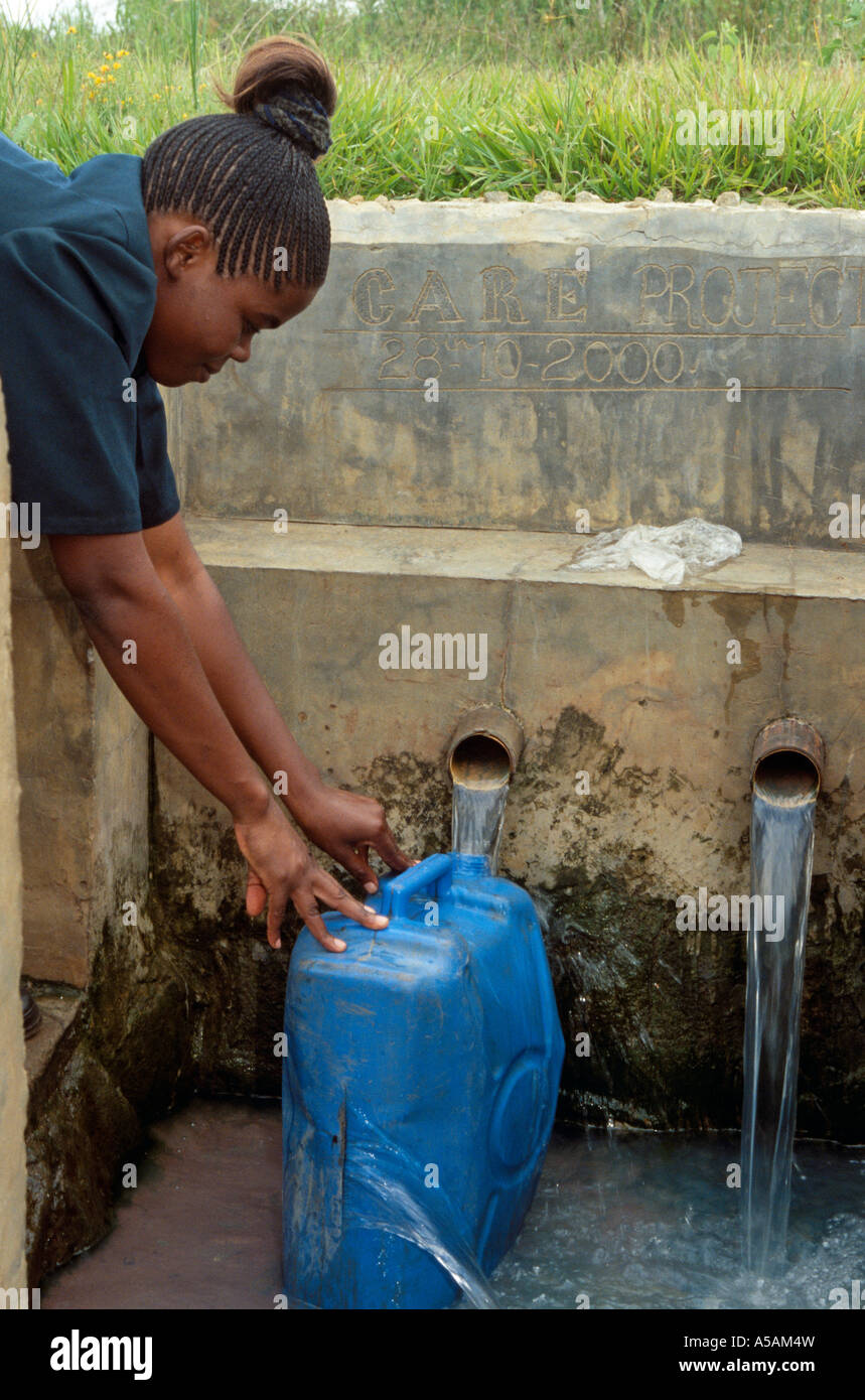 An African woman fills water from a running tap in Western Uganda ...