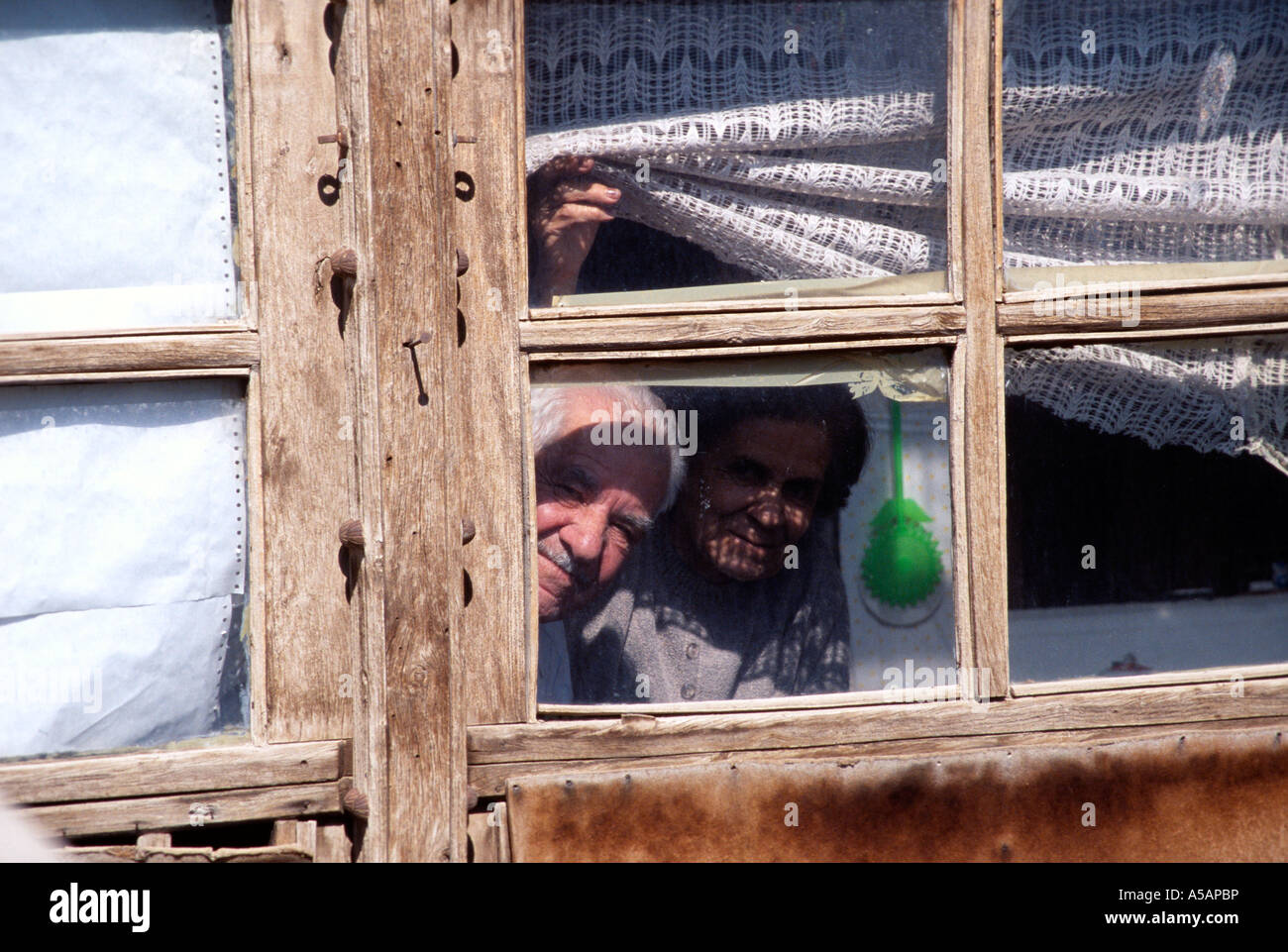 Senior couple residents peering through window, Armenian Quarters ...