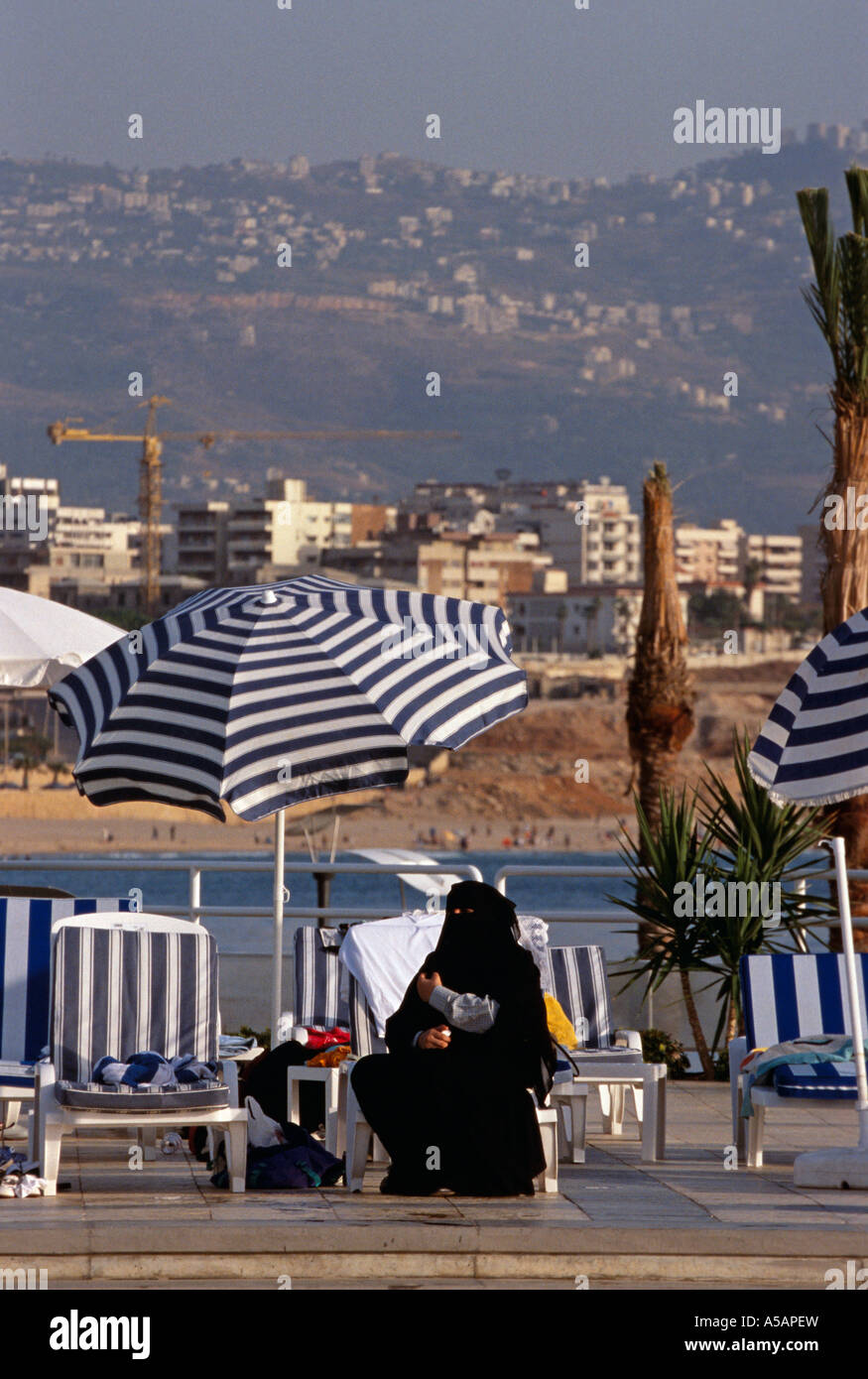 Muslim woman sitting at swimming pool near seaside, Beirut, Lebanon ...