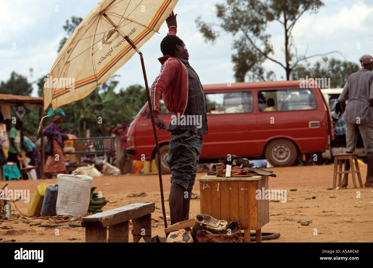 Cobbler stretching under parasol, Rwanda, Africa Stock Photo - Alamy