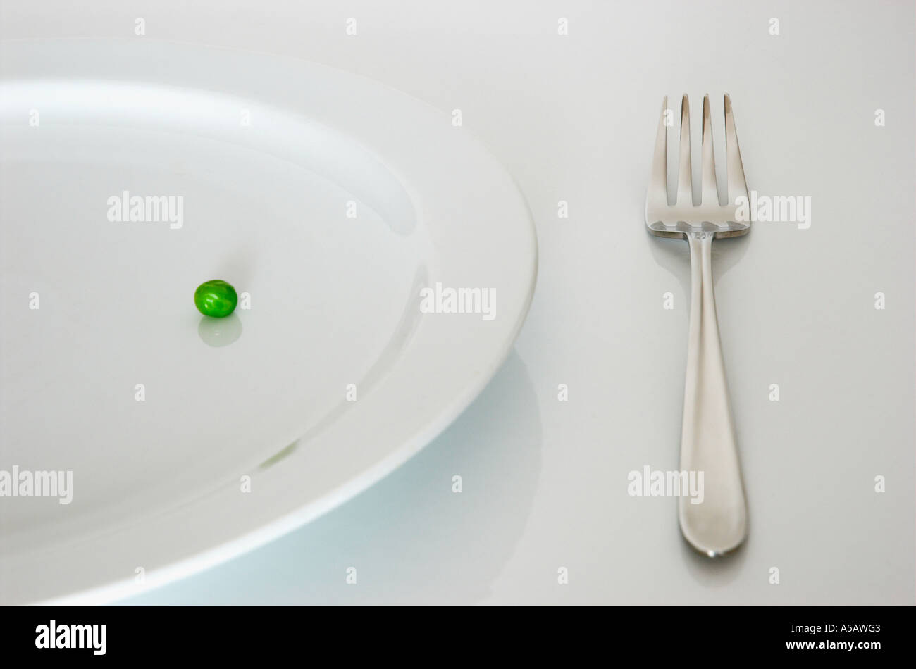 Pea on a plate with fork alongside Stock Photo - Alamy